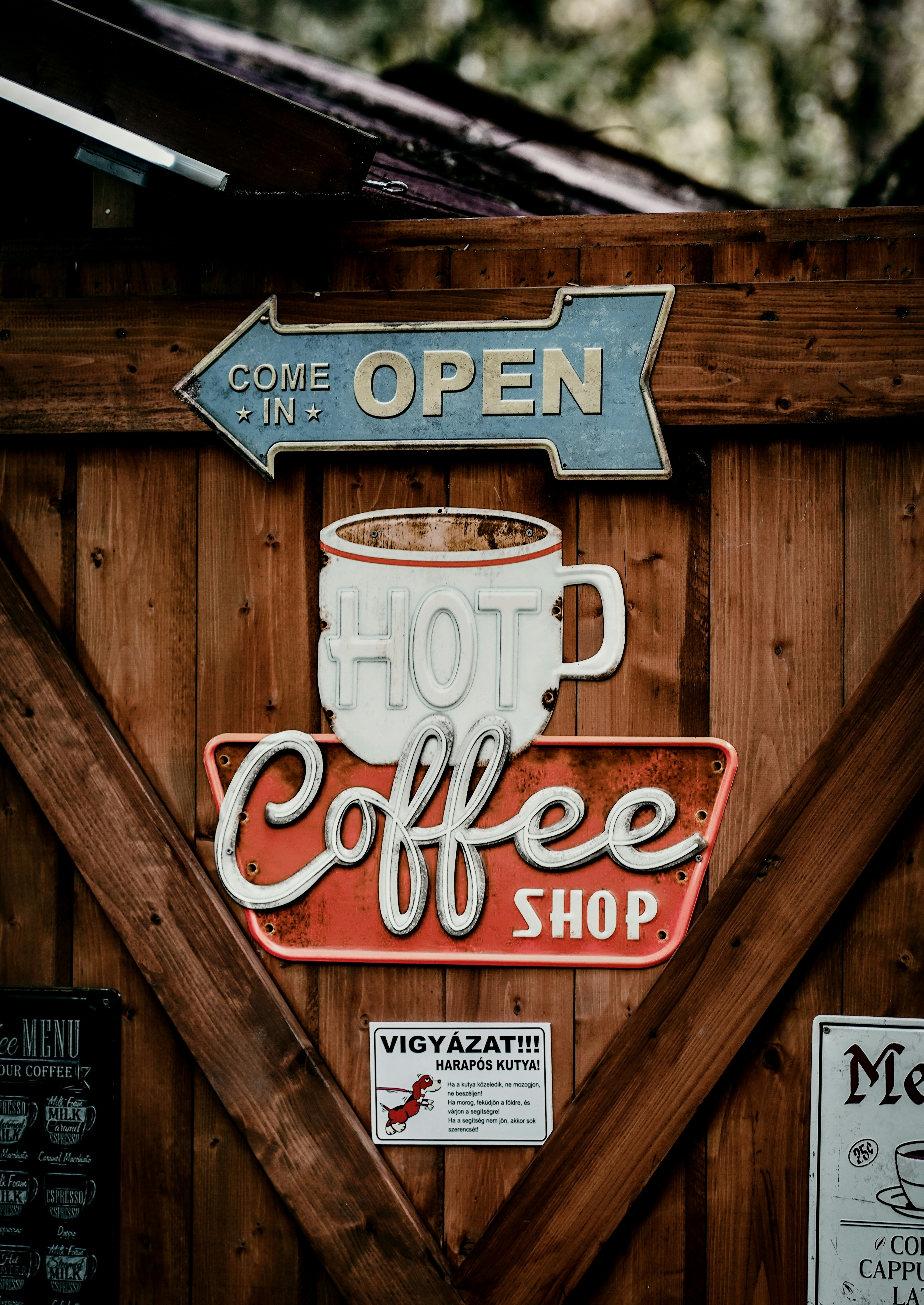 Open Signage and Neon Coffee Emblem on Rustic Wooden Gate