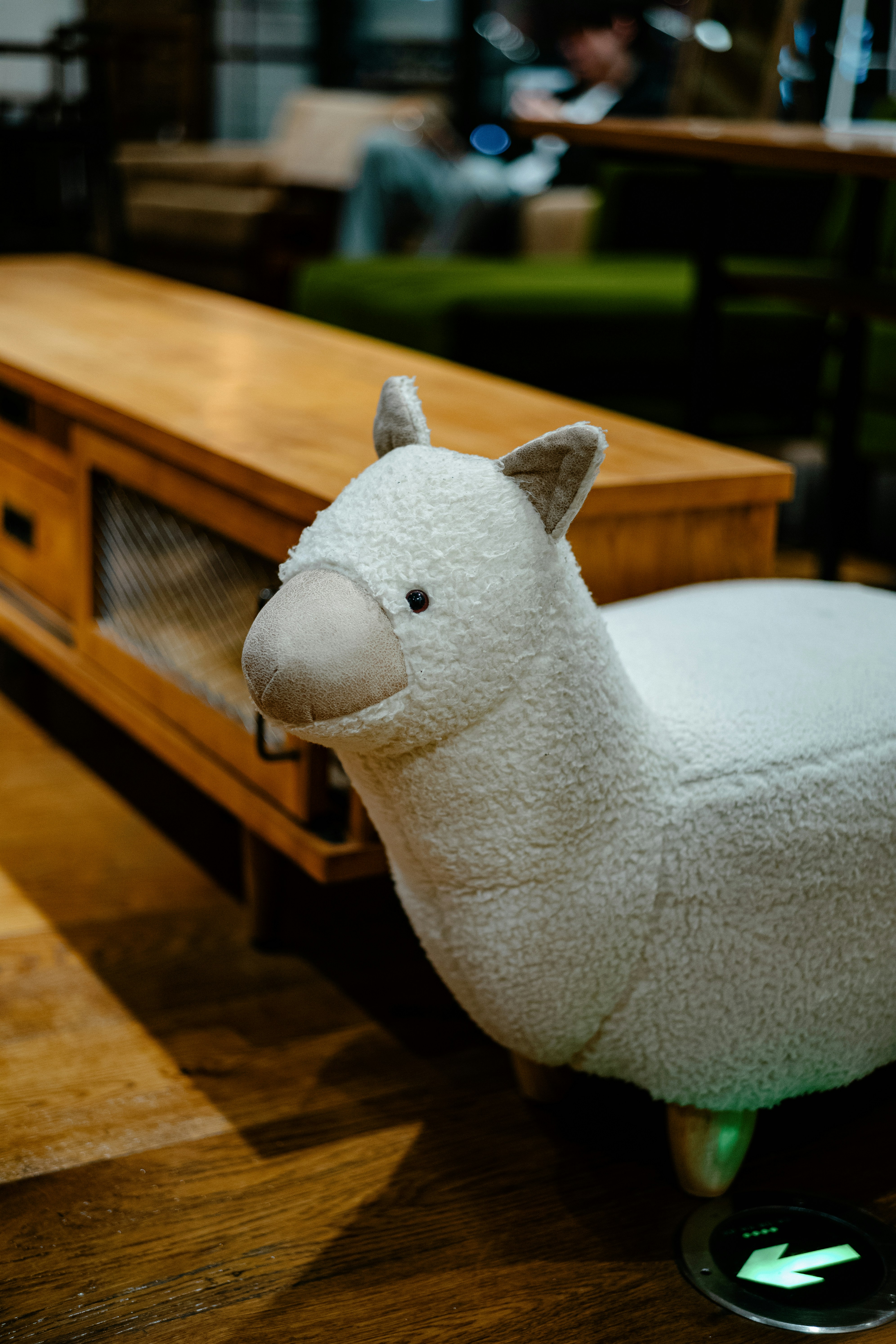 Llama in the Lounge: A Plush Sentinel Amid Warm Café Wood