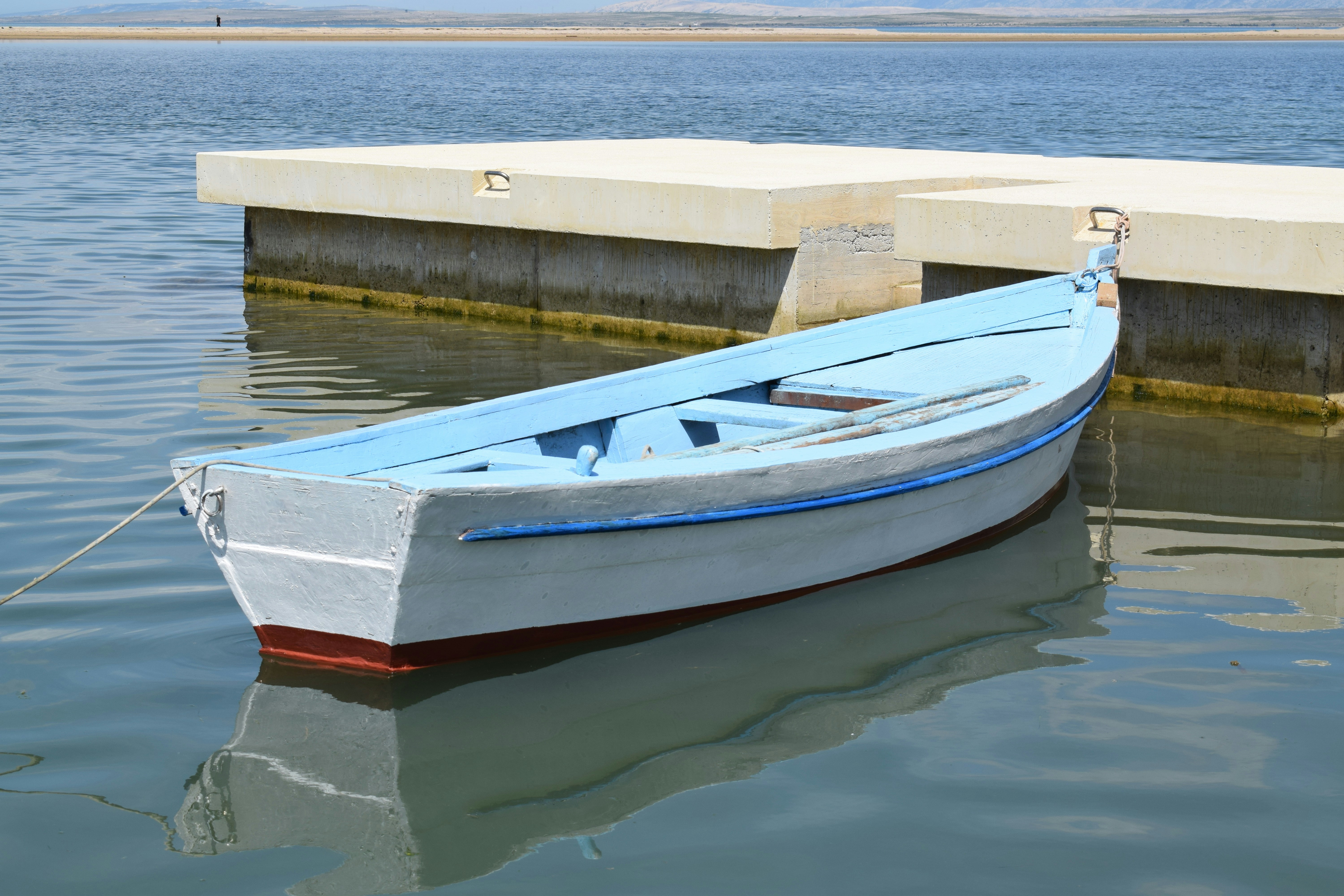 Foto zum Thema Ein kleines blau-weißes Boot, das an einem Dock ...