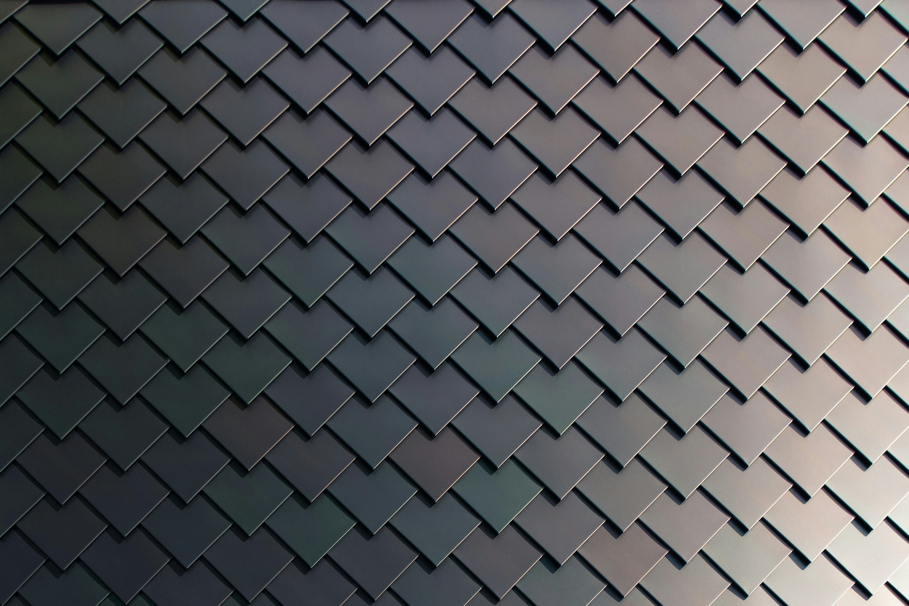 Close-up of a textured surface featuring interlocking diamond-shaped tiles in varying shades of gray. The pattern creates a sense of depth and rhythm.