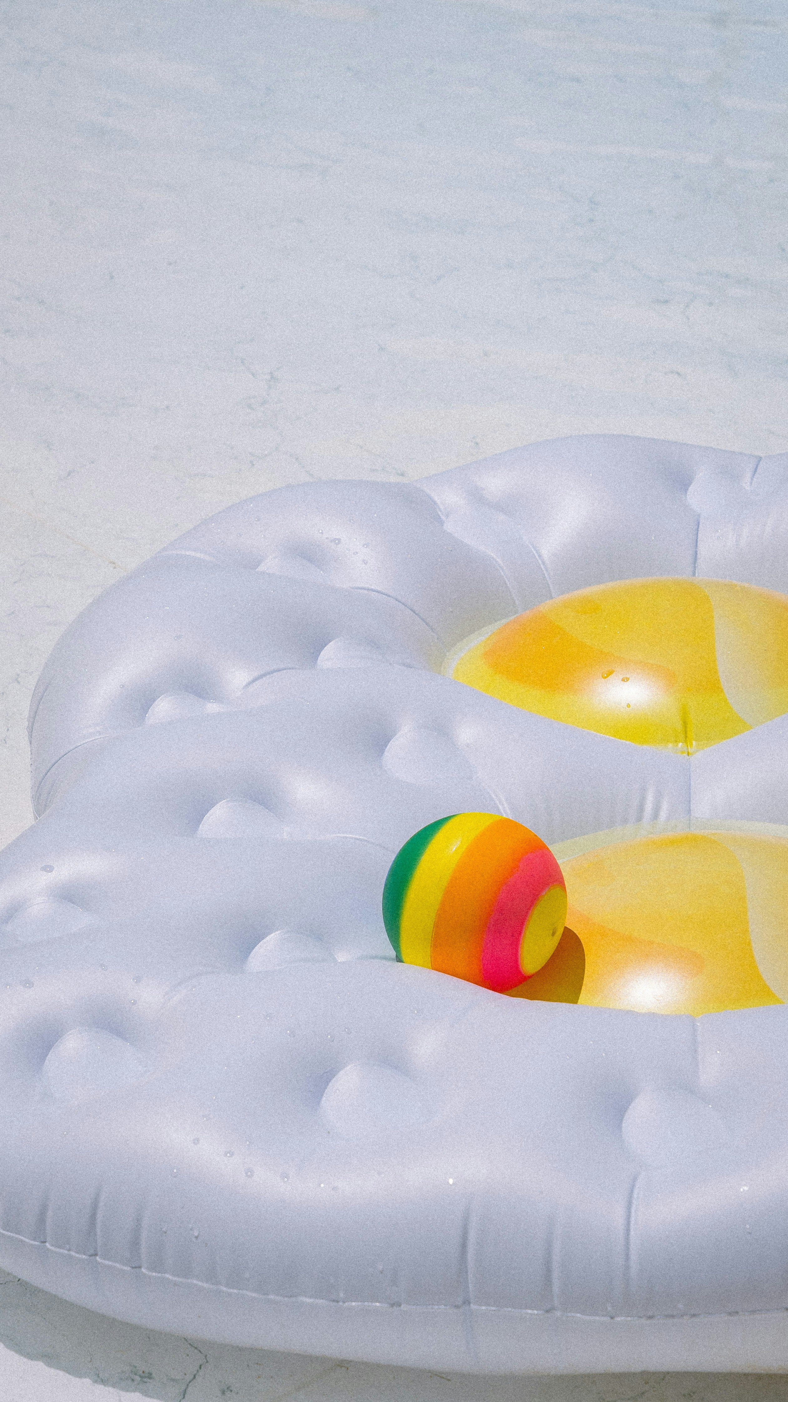 Sunlit Float: A Rainbow Ball Adrift on a Puffy Oasis