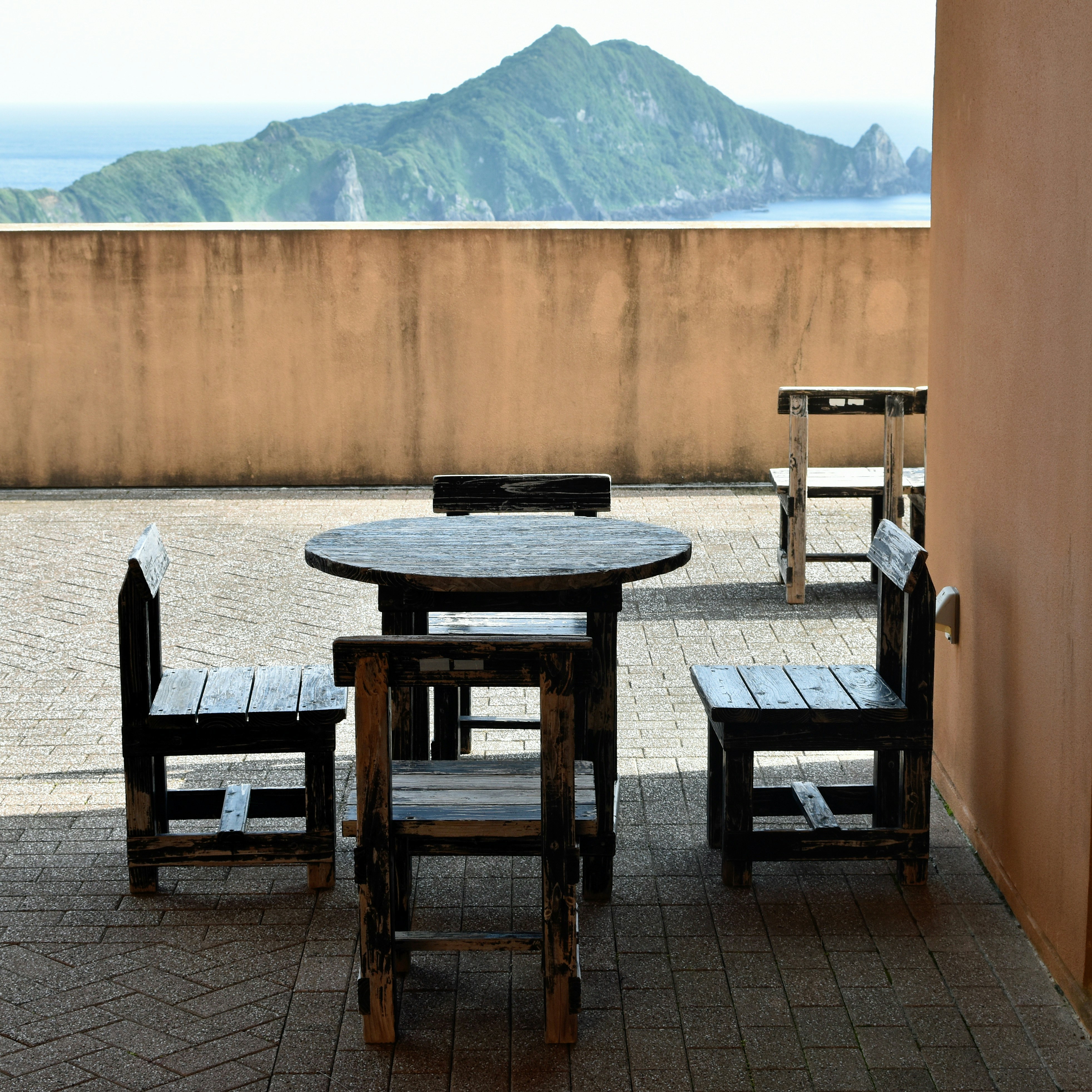 a table and chairs on a patio with a mountain in the background