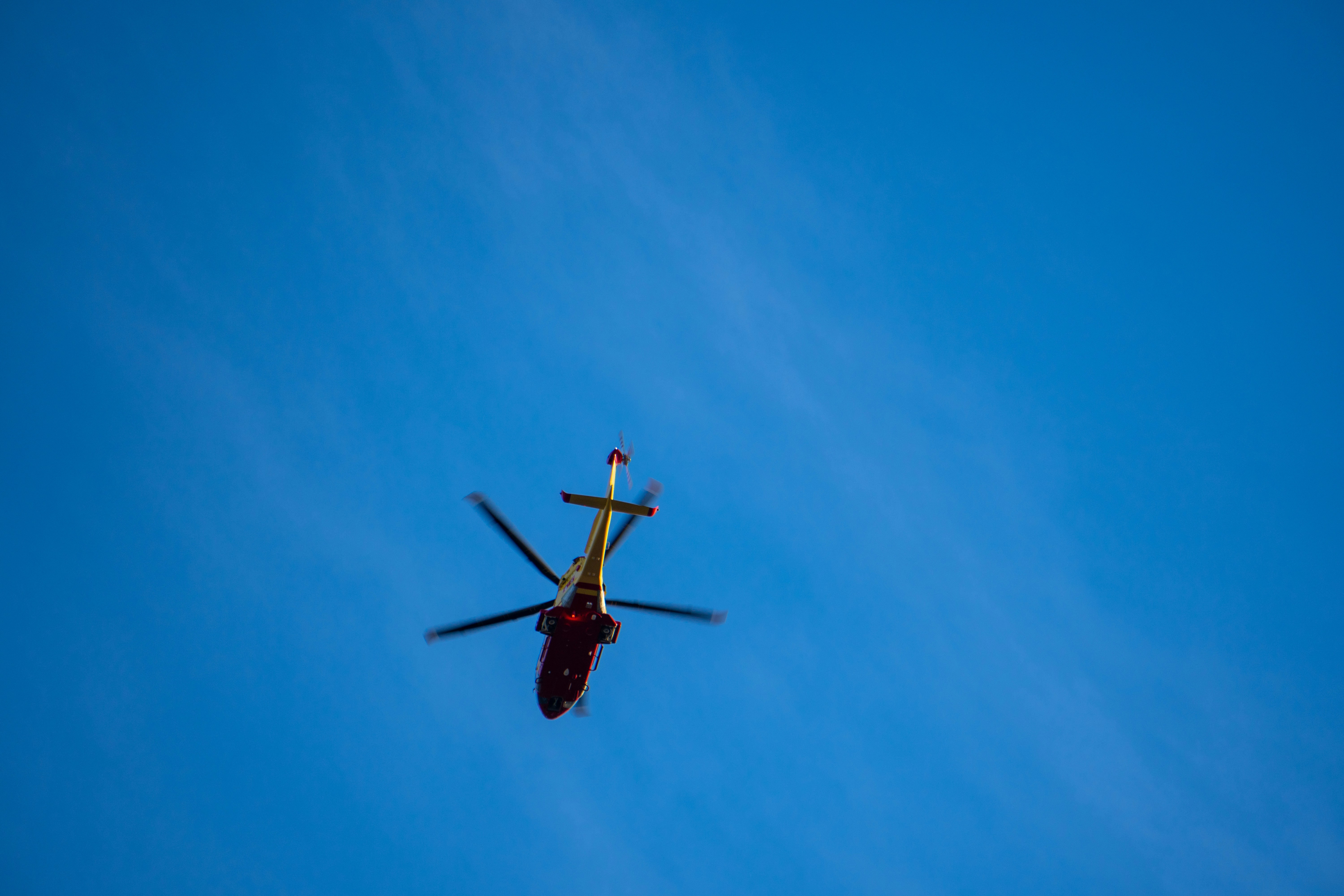 Red Rescue Helicopter Weaves Through a Clear Azure Sky