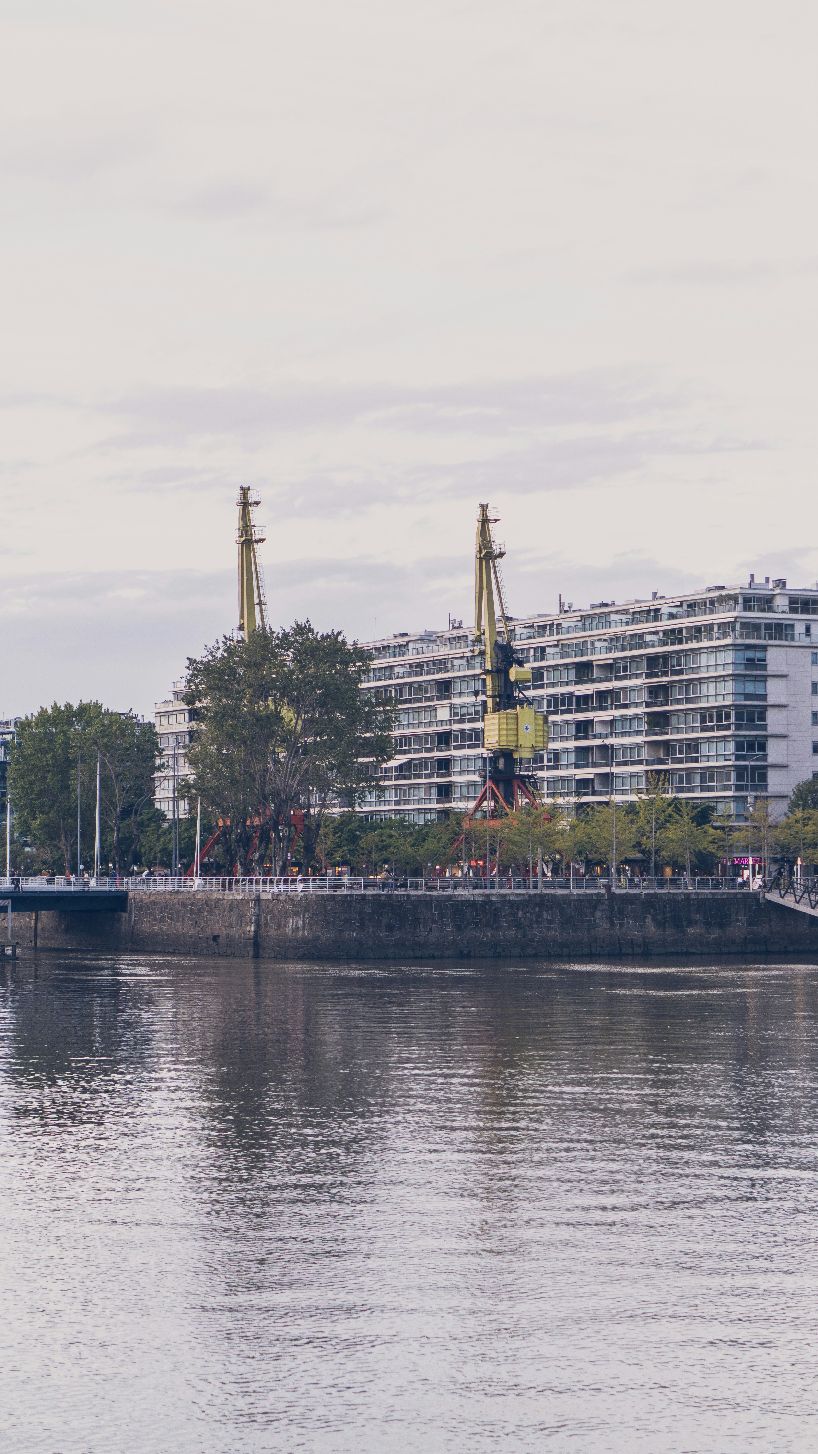 Industrial waterfront with yellow cranes towering over modern apartments