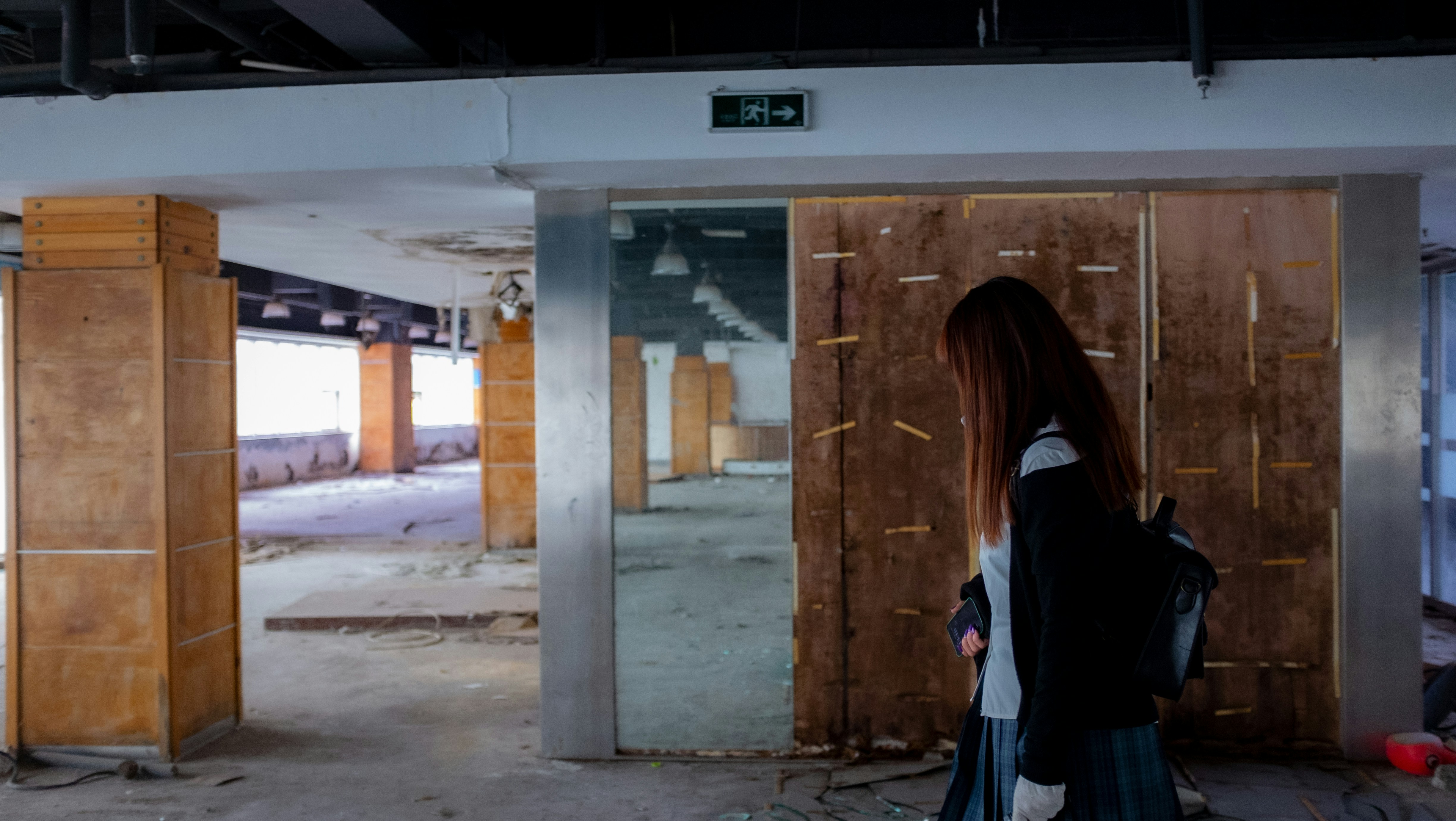 Sheltered Between Framing: A Student Pauses in an Unfinished Concrete Hall