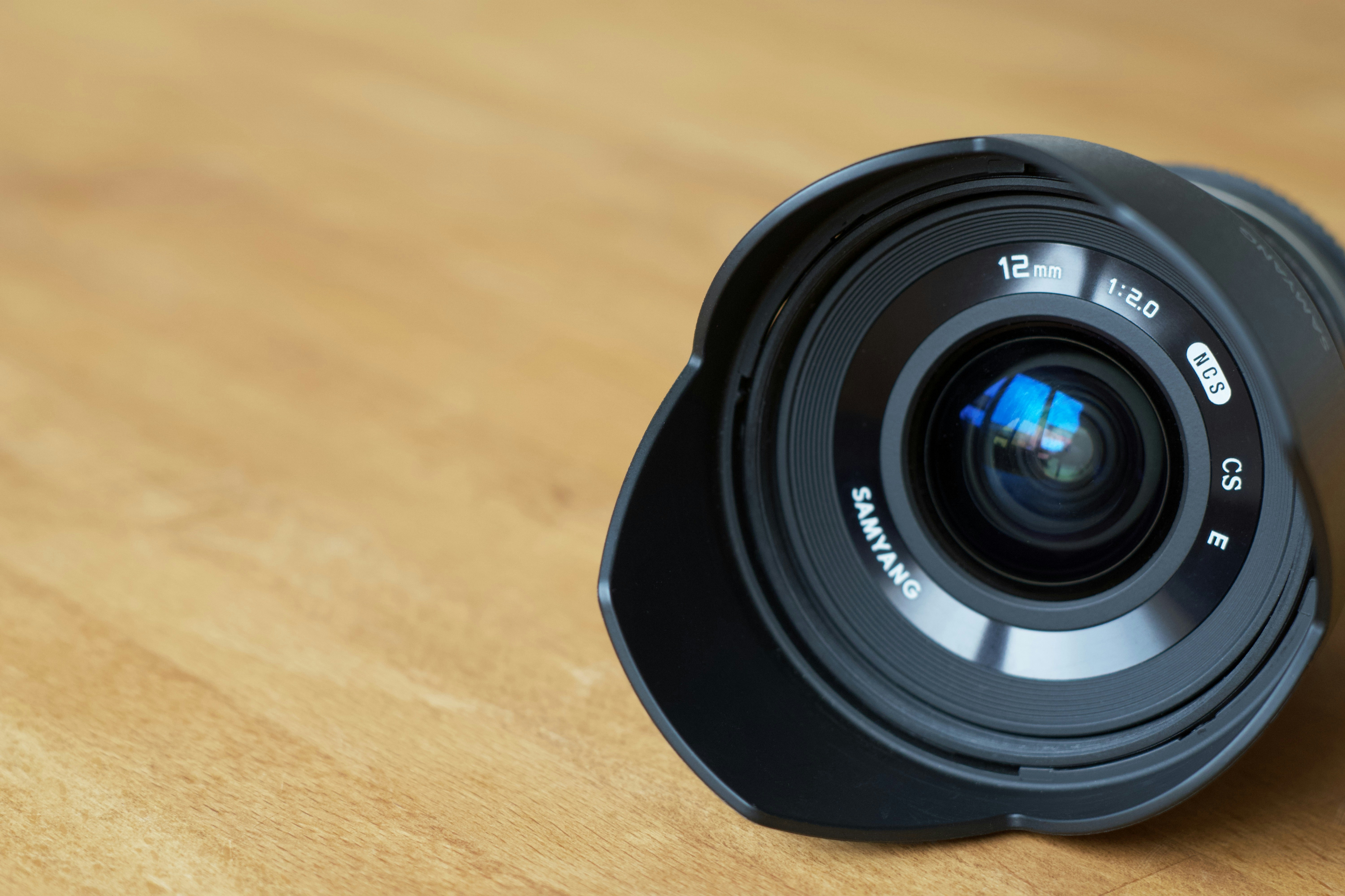 A camera lens sitting on top of a wooden table photo – Free Camera ...