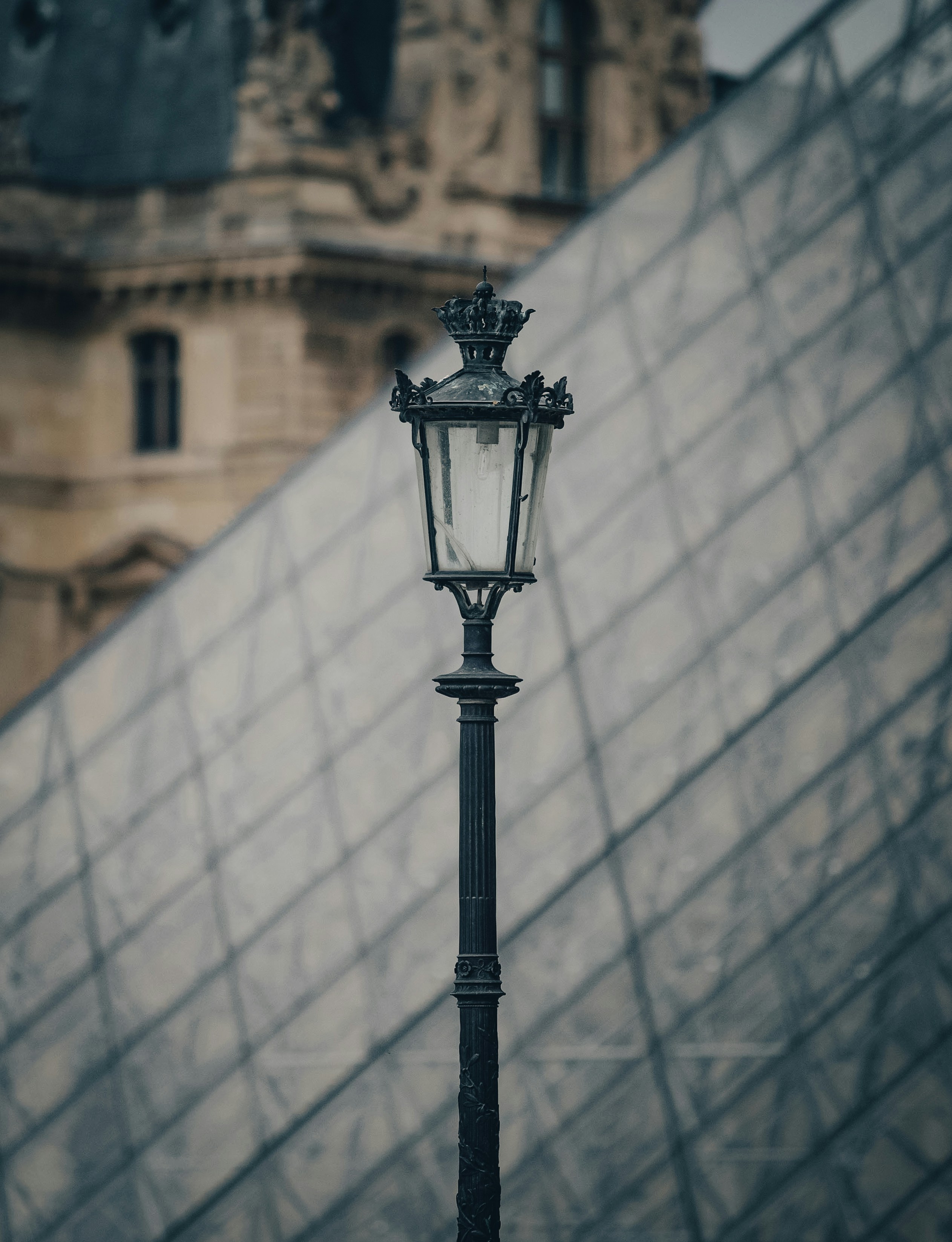 Gaslit Sentinel: A Street Lamp Framed by Architectural Glass and Stone