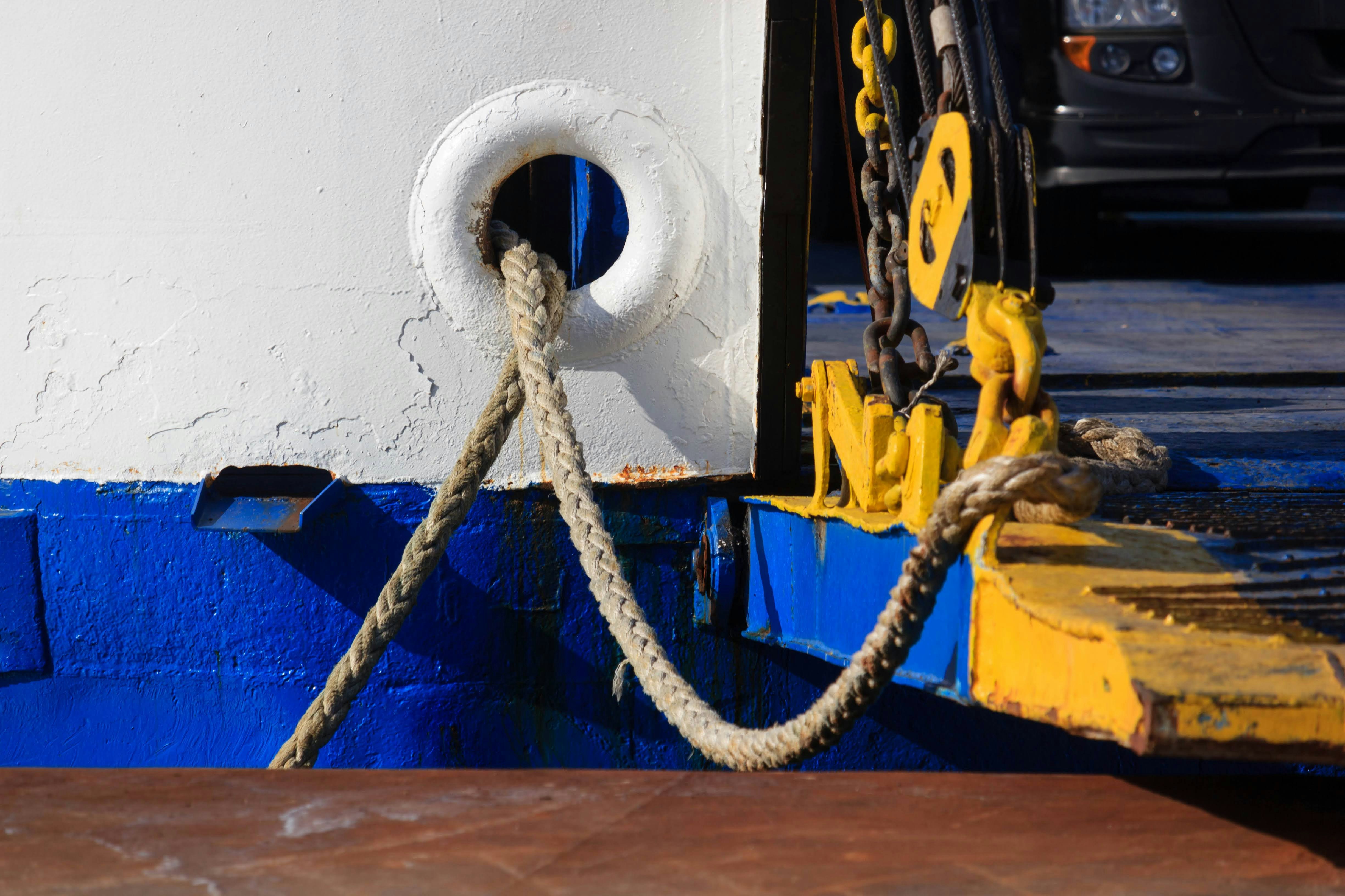 Mooring Ballet at the Hull Edge: Coiled Rope Framing Blue Stripe and Yellow Dock Hardware