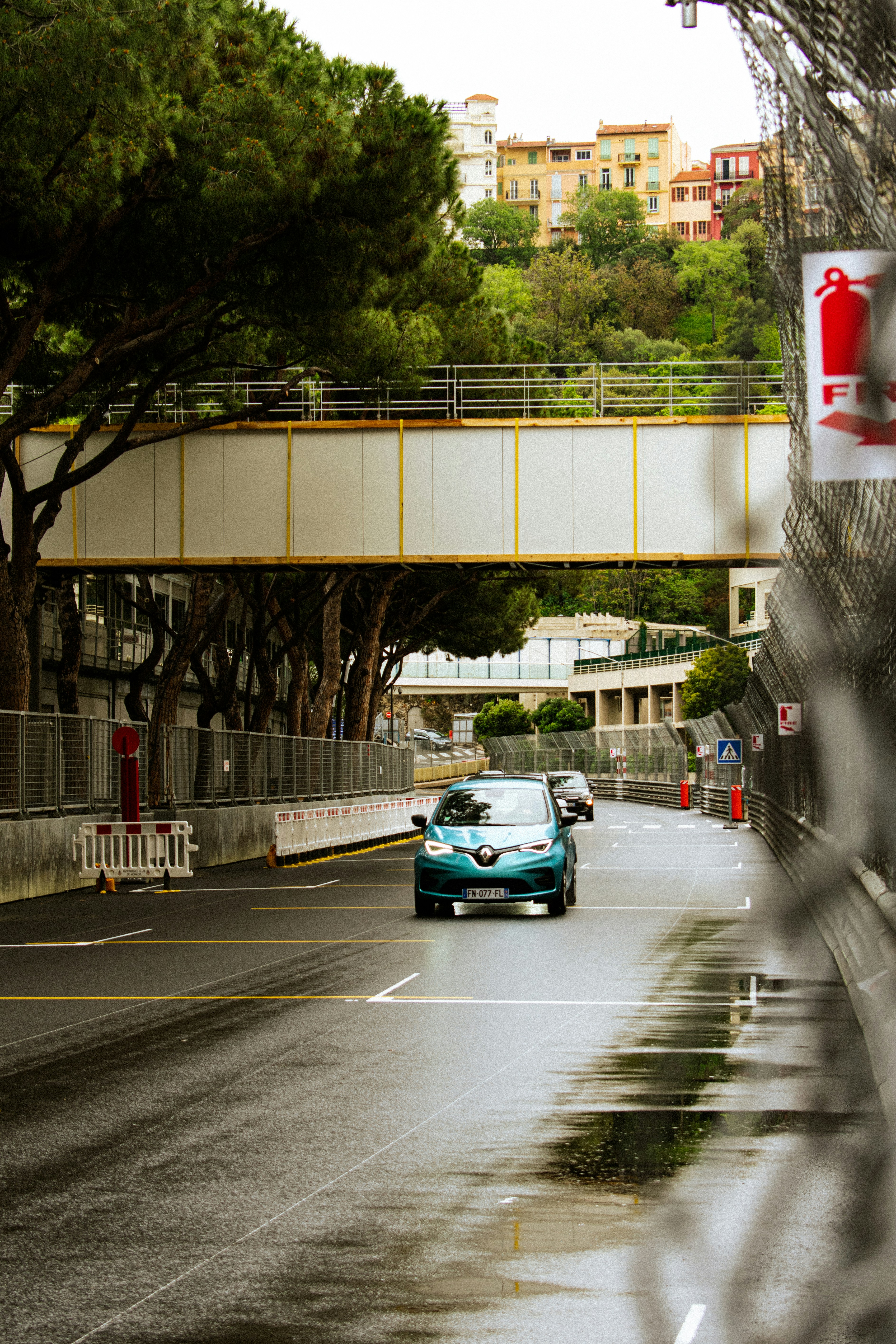 A blue car driving down a street next to a bridge photo – Free Monaco ...