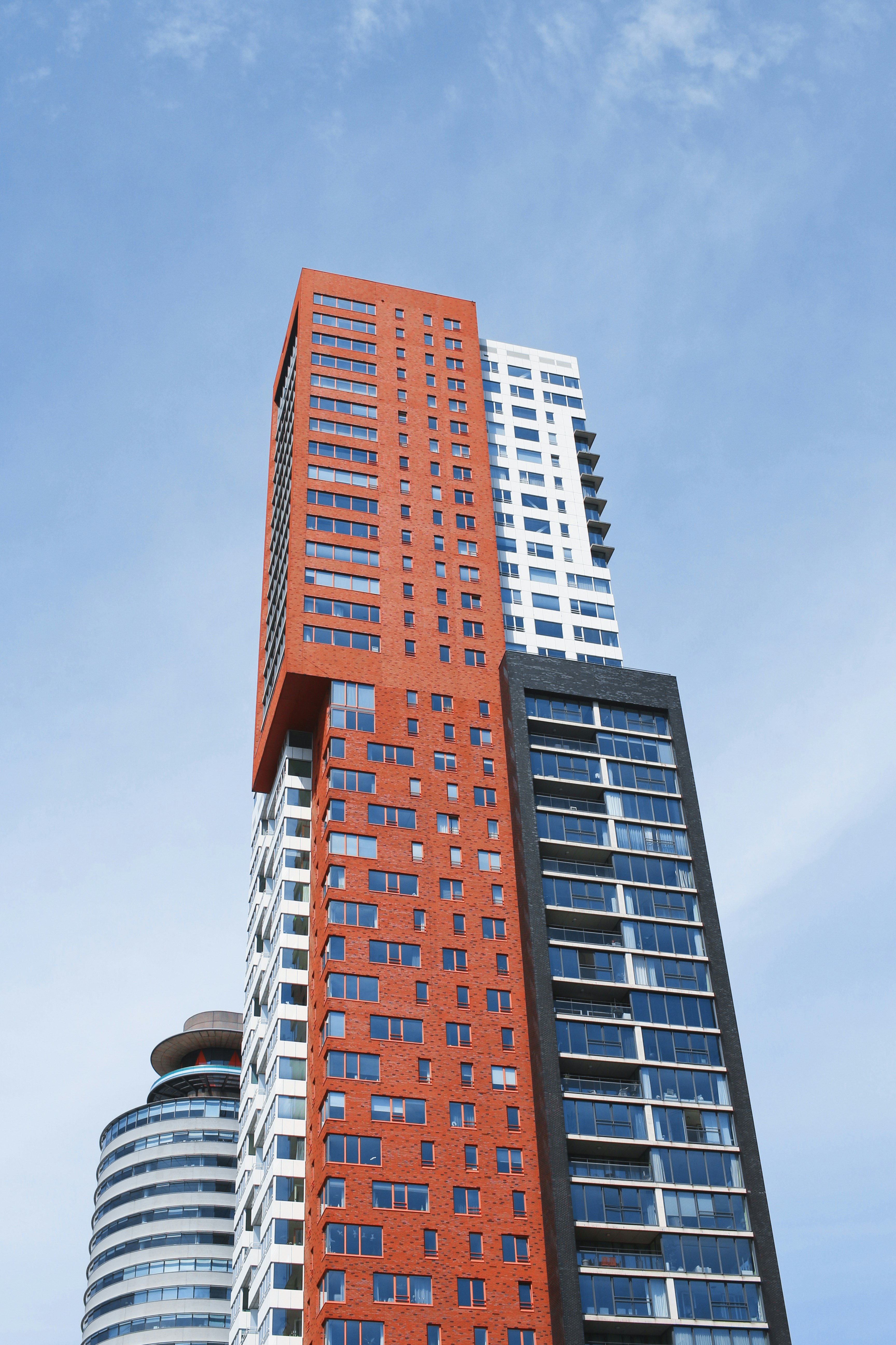 A tall red brick building next to a tall white building photo – Free ...