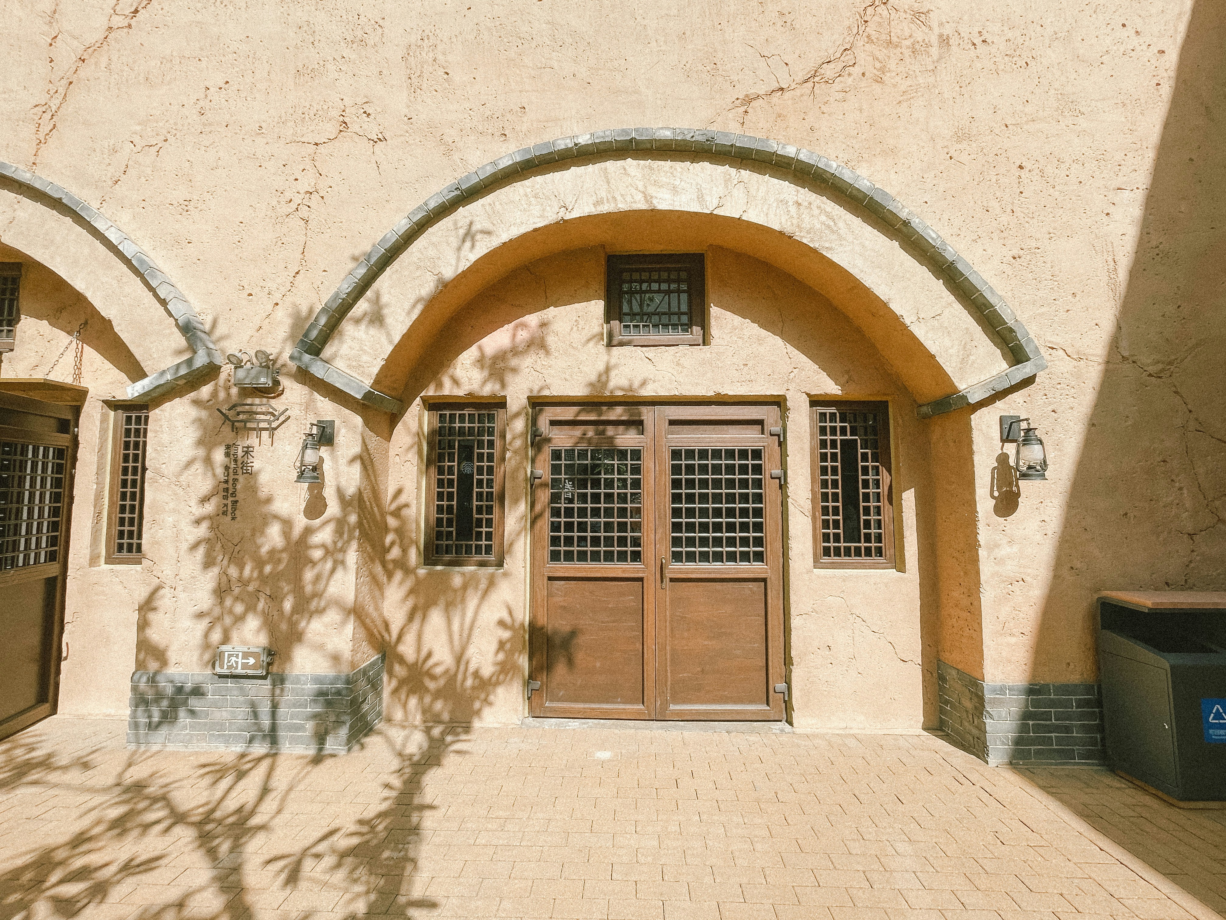 A tan building with two brown doors and two windows photo – Free ...