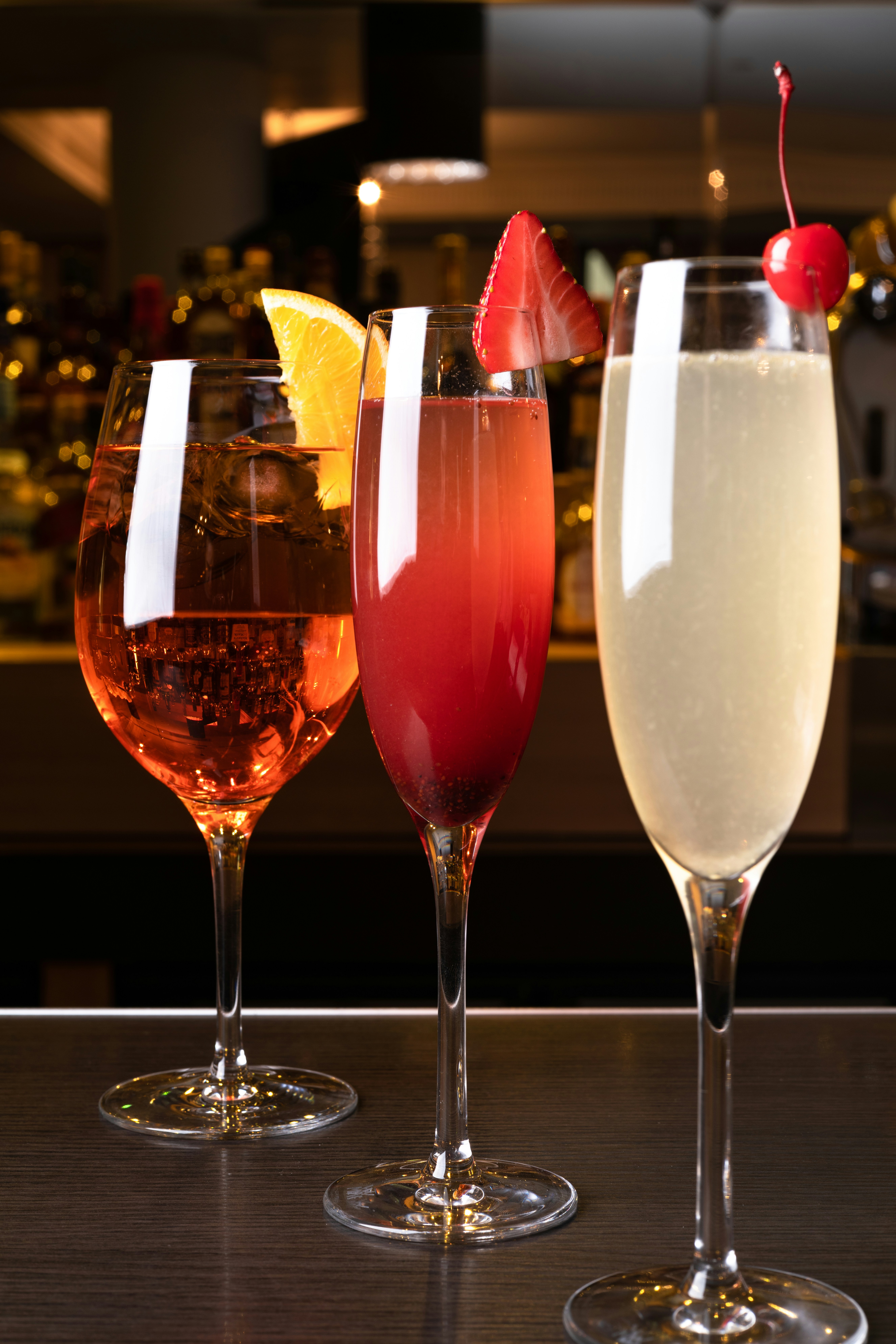 Triad of Garnished Glasses: Amber, Crimson, and Pearl on a Bar