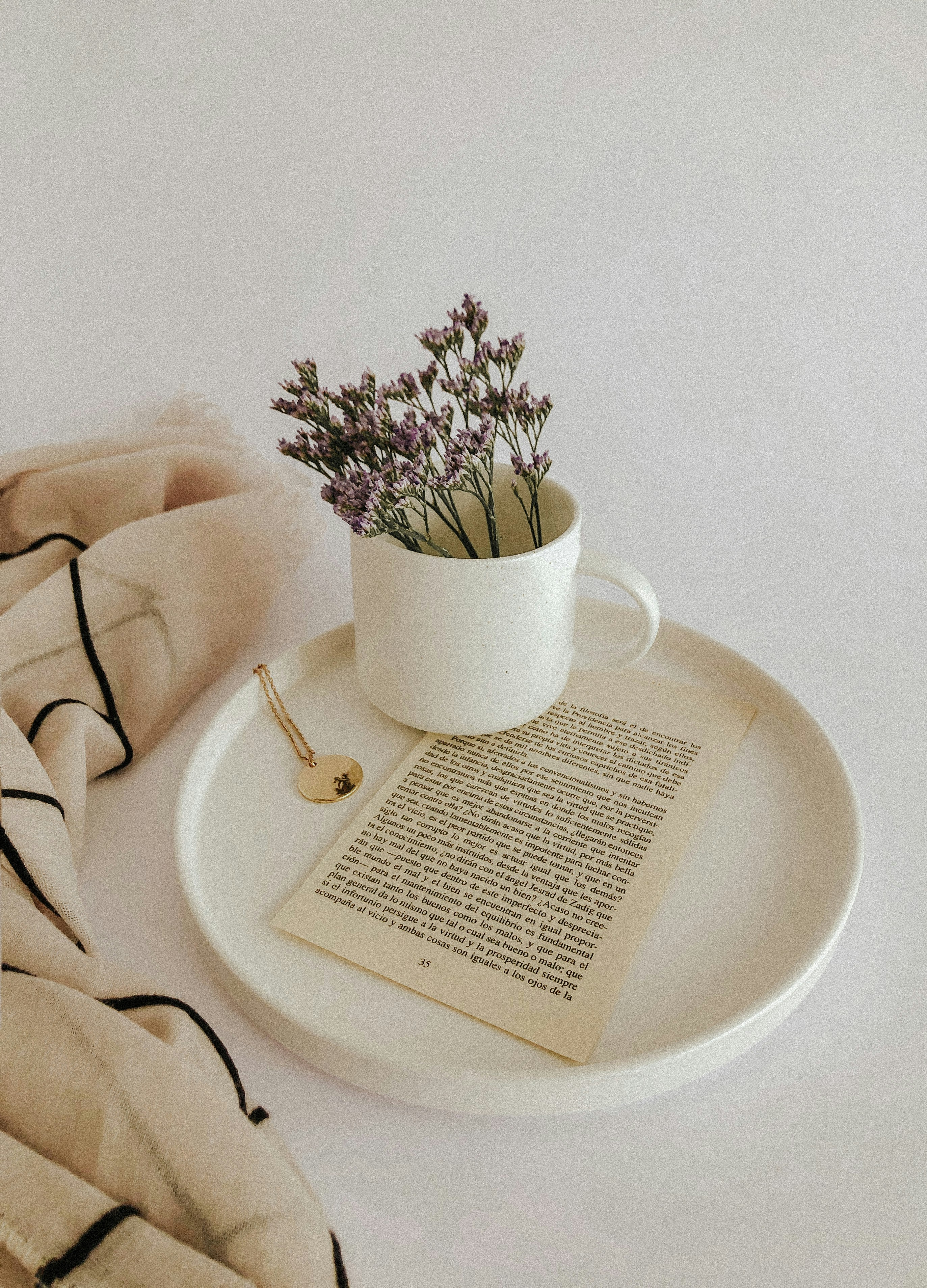 White plate with book page, flowers and scarf