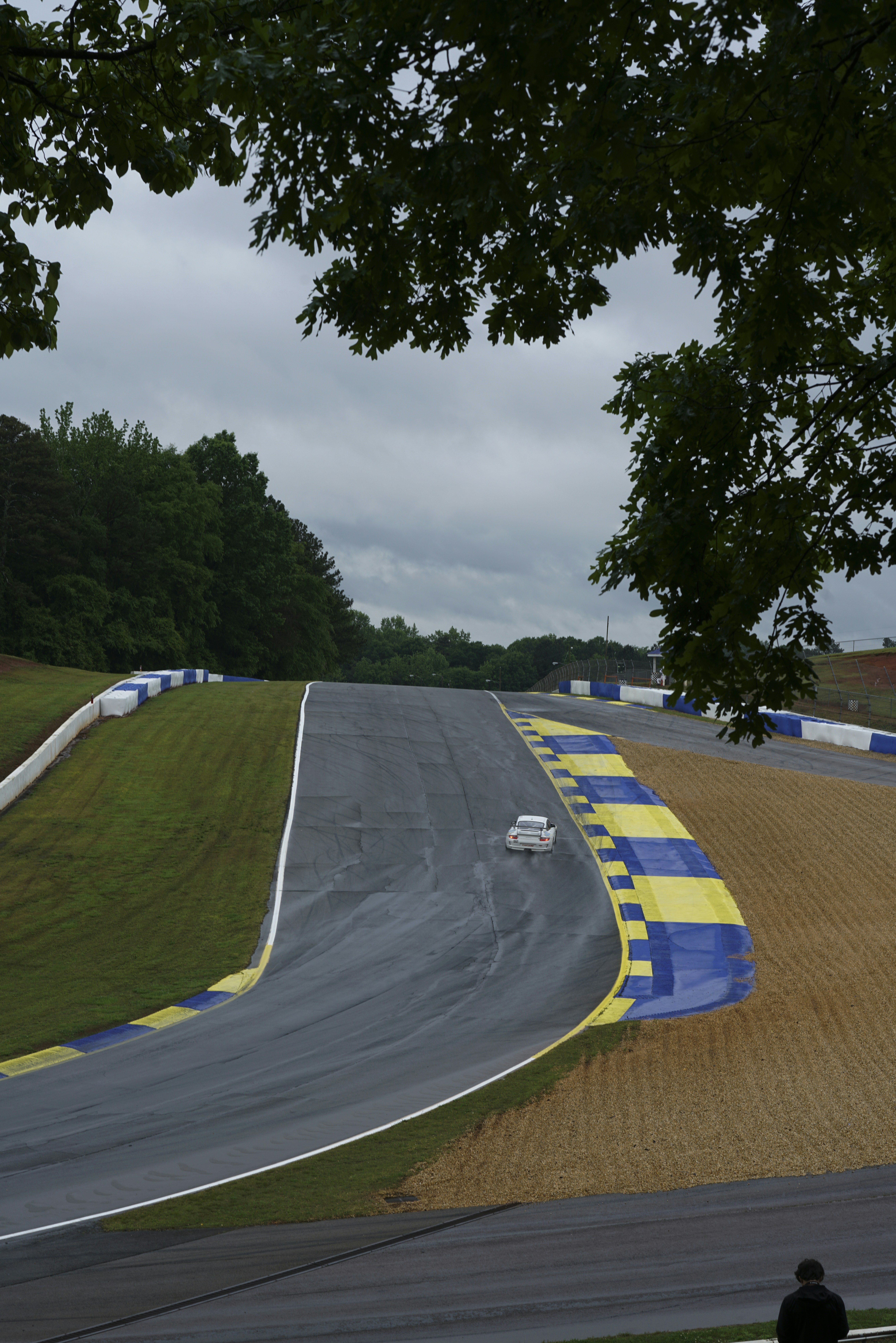 Rain-Kissed Curve: A Lone Car Carving the Blue-Yellow Arc on a Damp Circuit