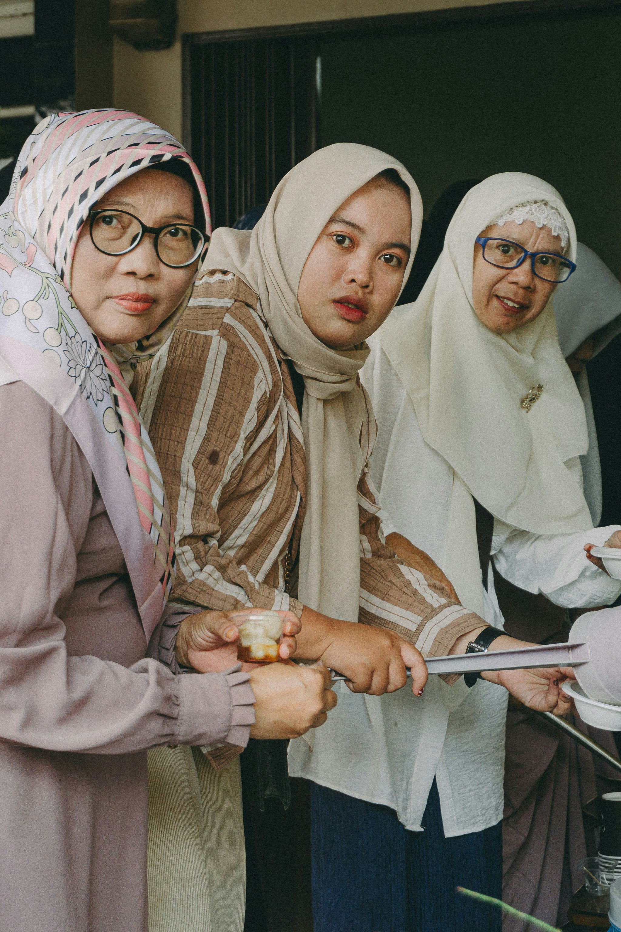 Stallside Trio: Three Hijab-Clad Friends in a Street Kitchen Moment