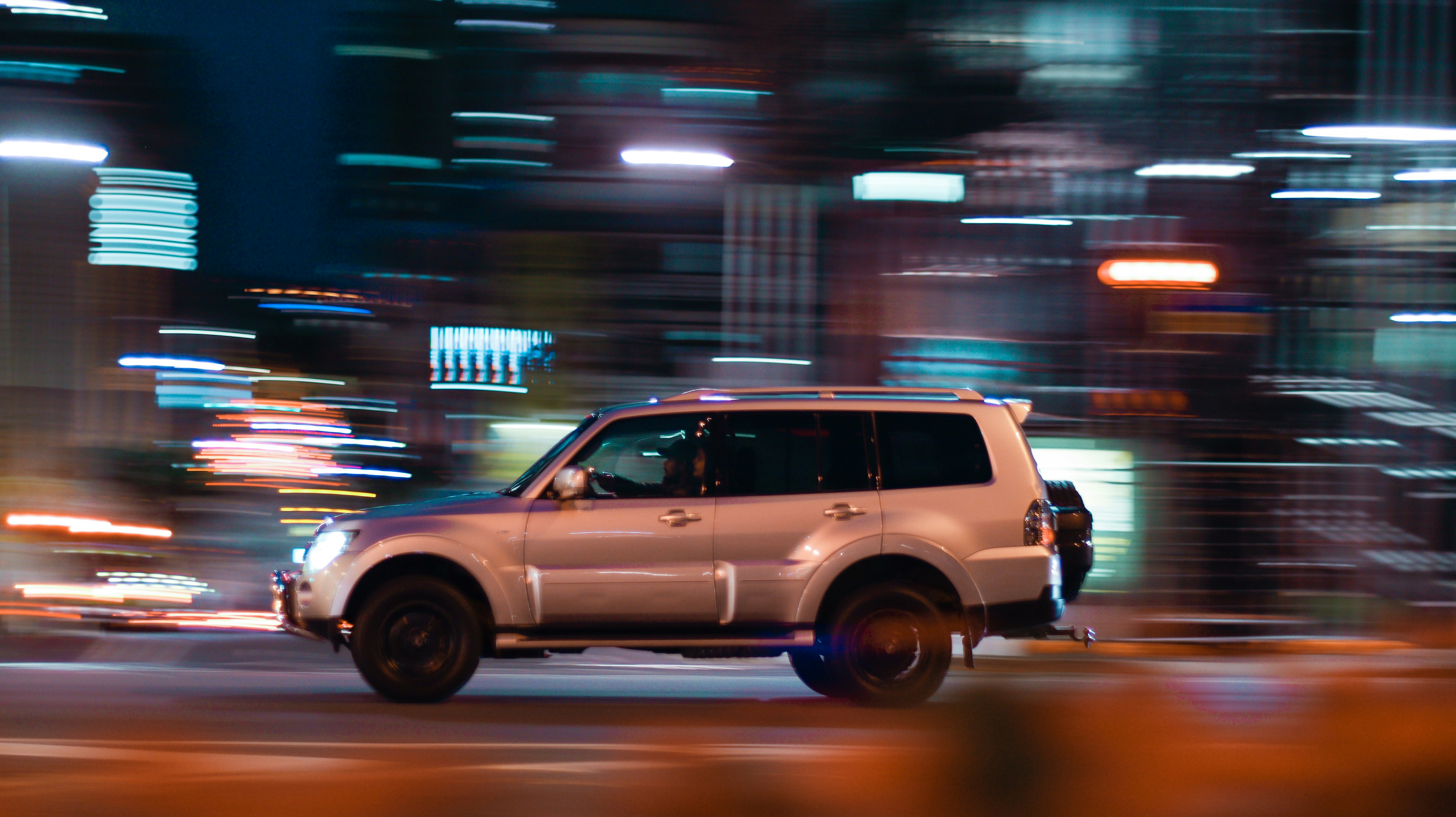 Midnight Blur: a silver SUV carving through neon-lit city streets