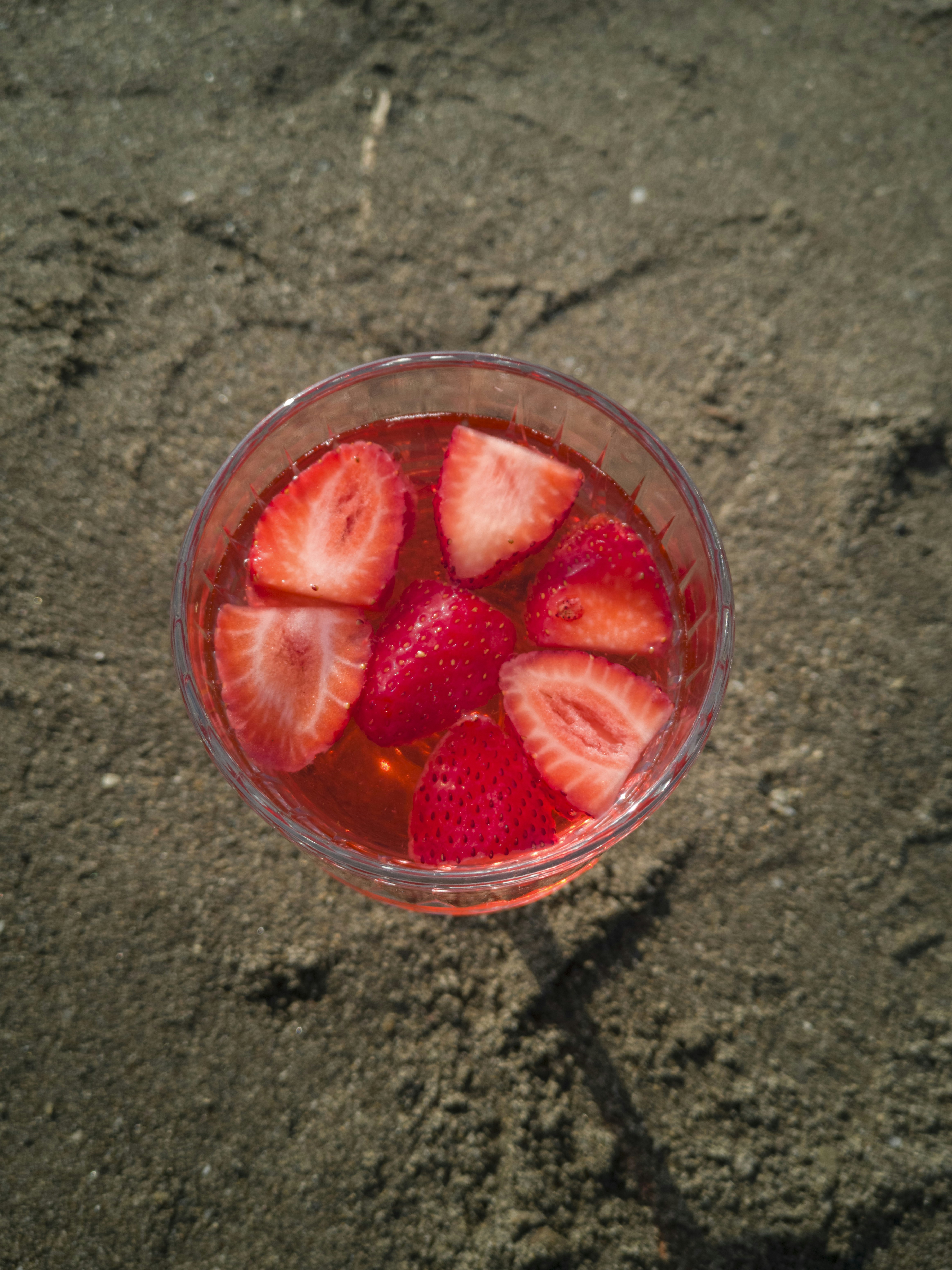 Strawberry Infusion in a Glass on Sunlit Sand