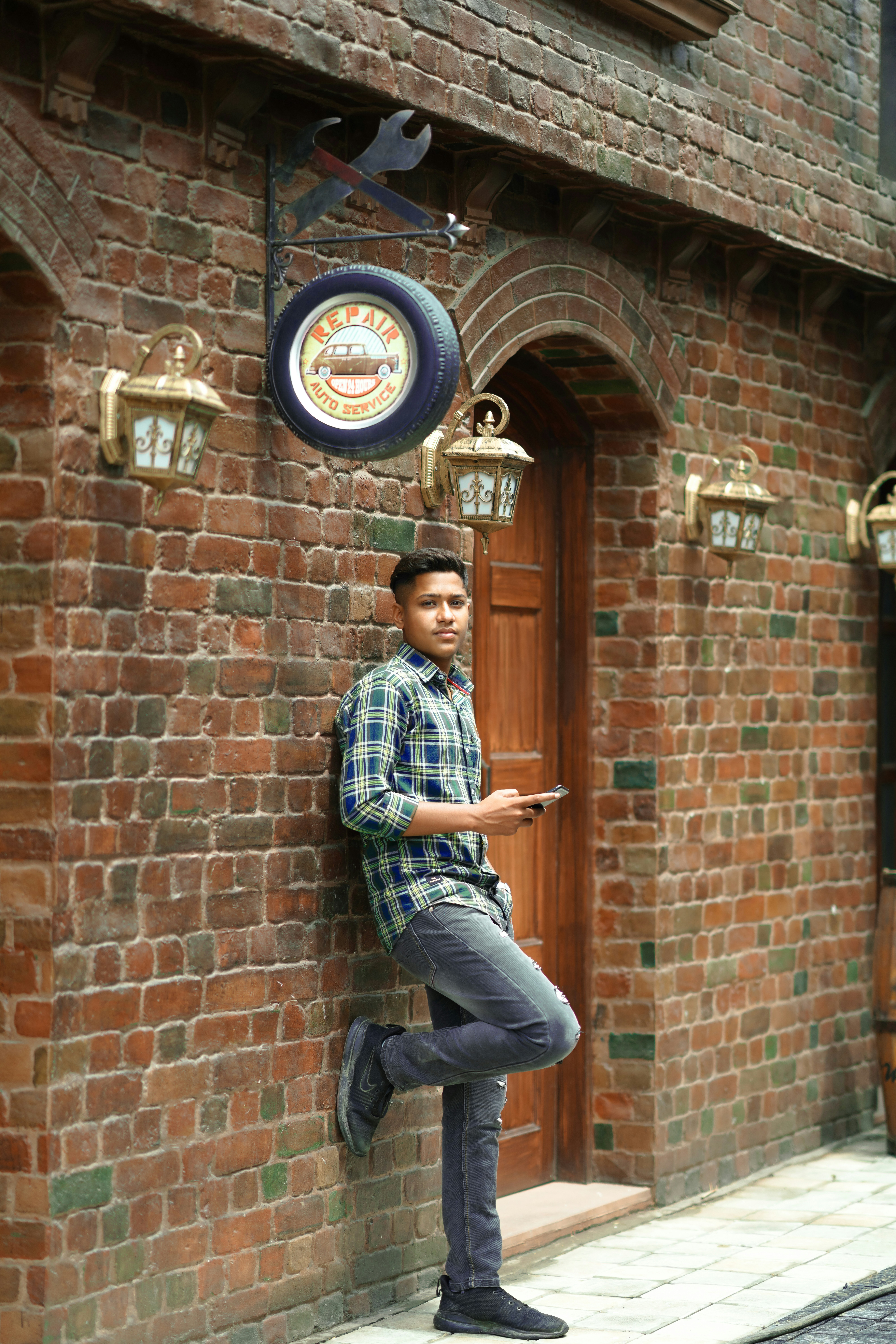 Casual doorway guardian: a man in plaid lingers beside a brick inn
