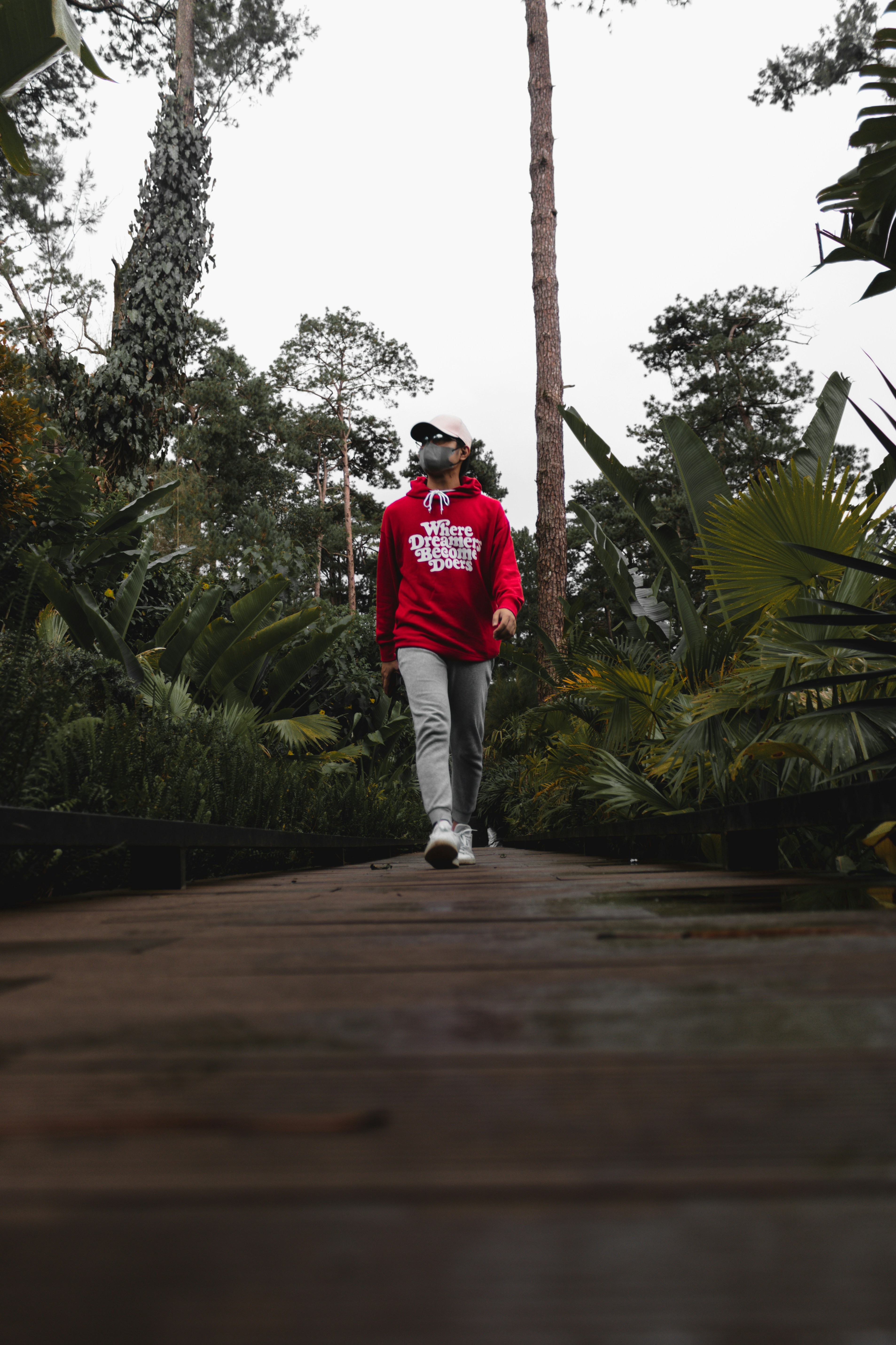 Red Hoodie Voyager on a Wooden Path Amid Tropical Stillness