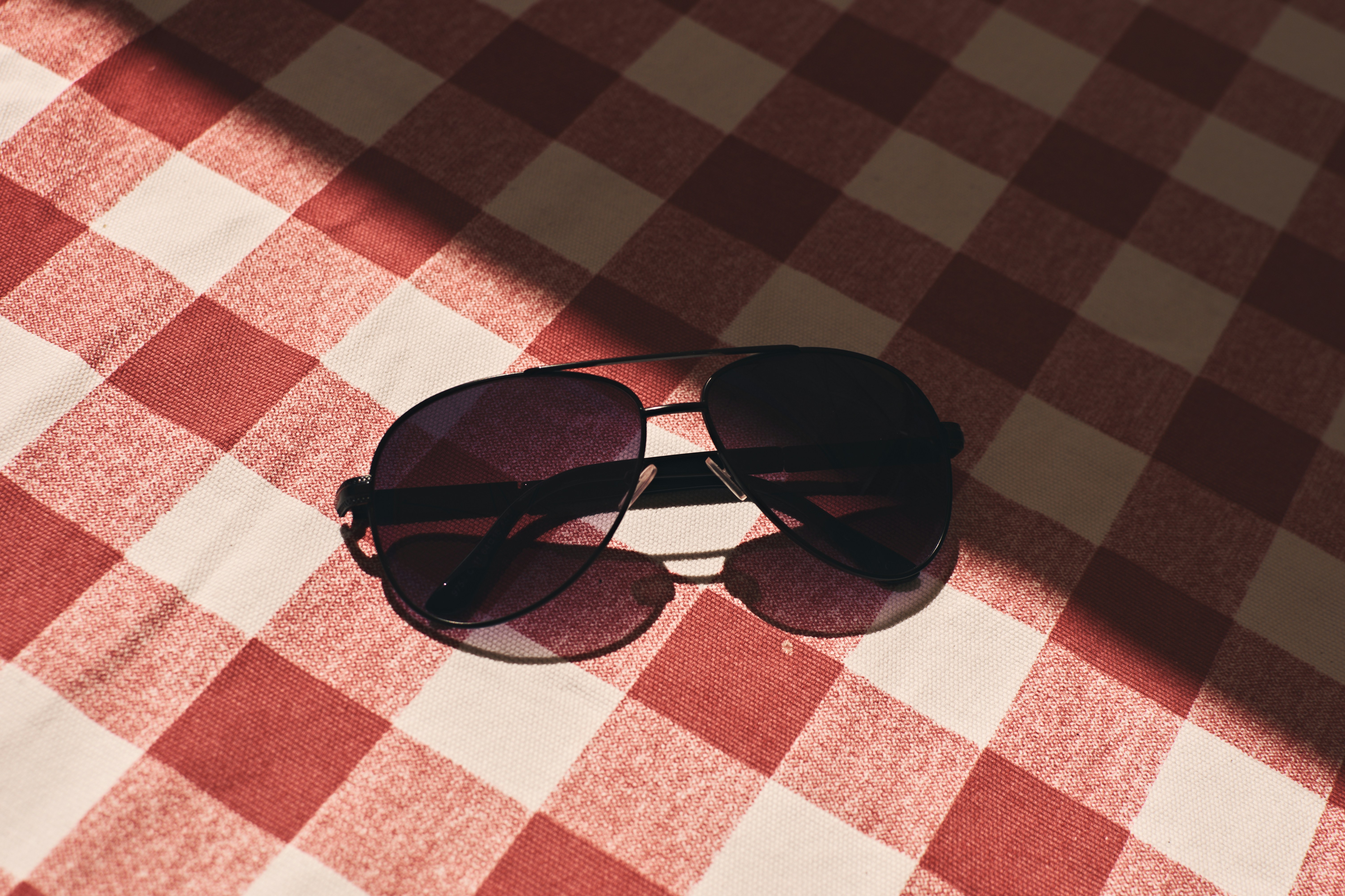Glare and Geometry: Sunglasses on a Sunlit Checkered Table