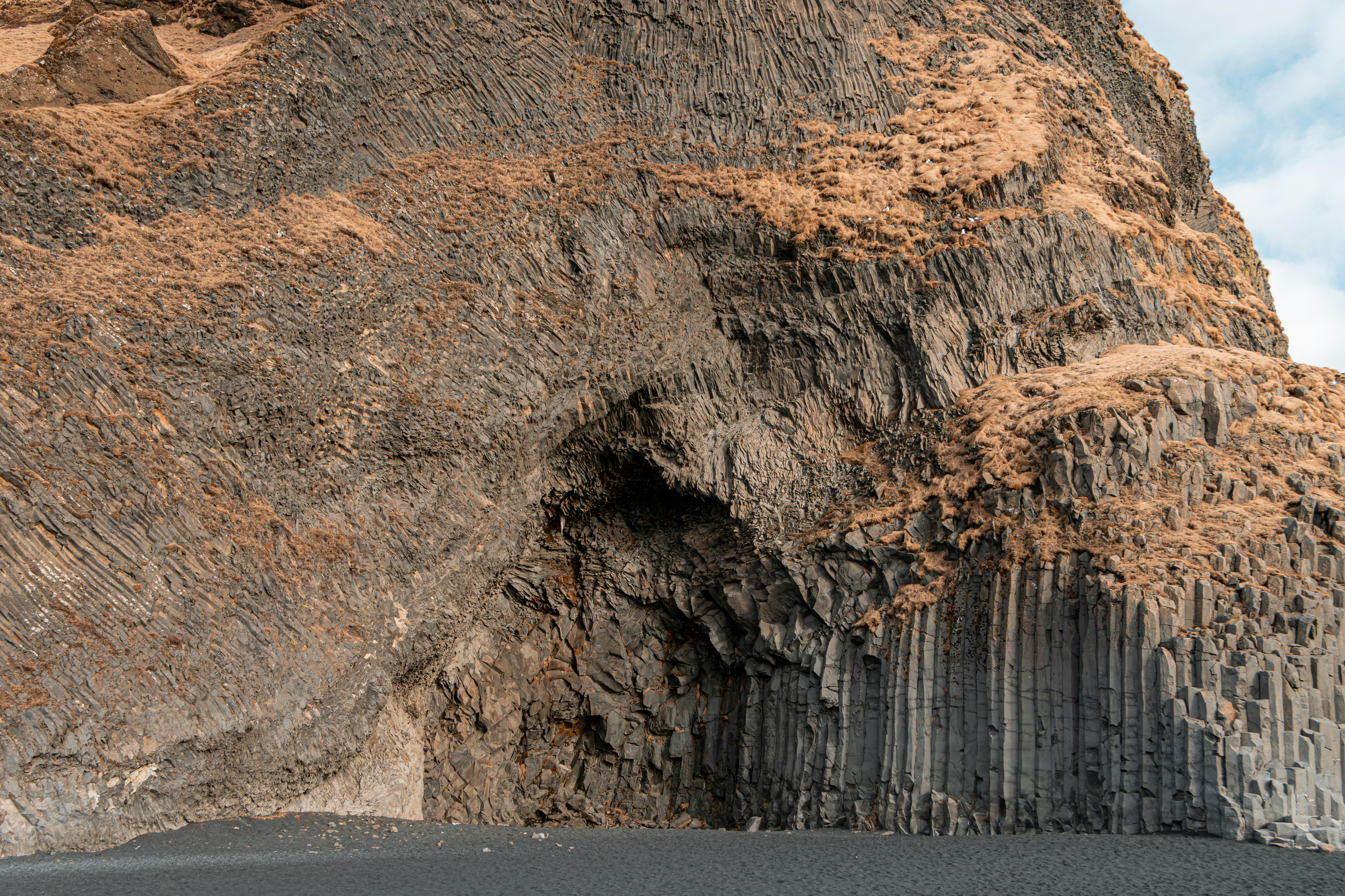 Shadowed Basalt Cavern Framing a Black Sand Shore