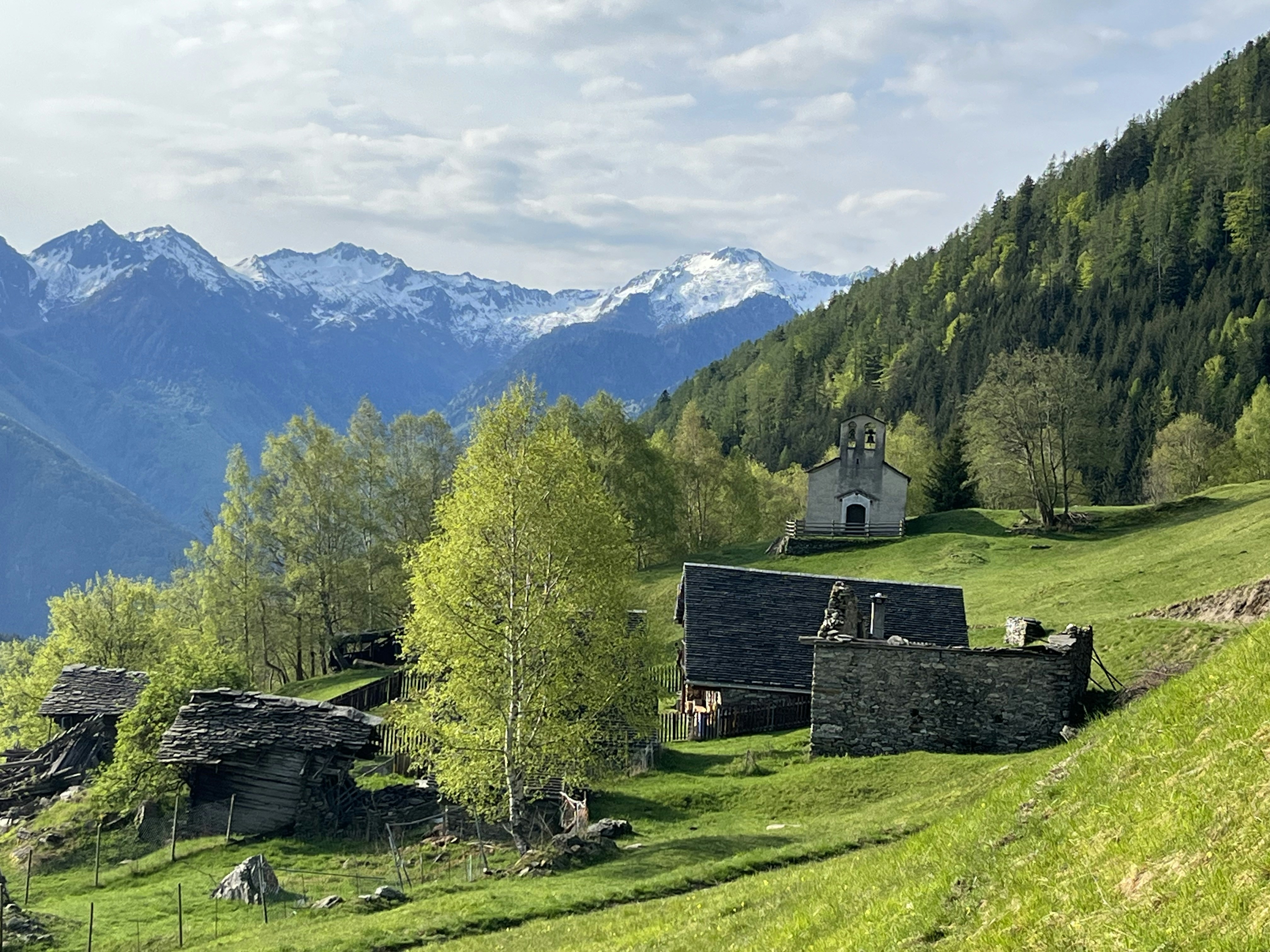 Hilltop Chapel Among Stone Cottages Beneath Snow-Dusted Alps