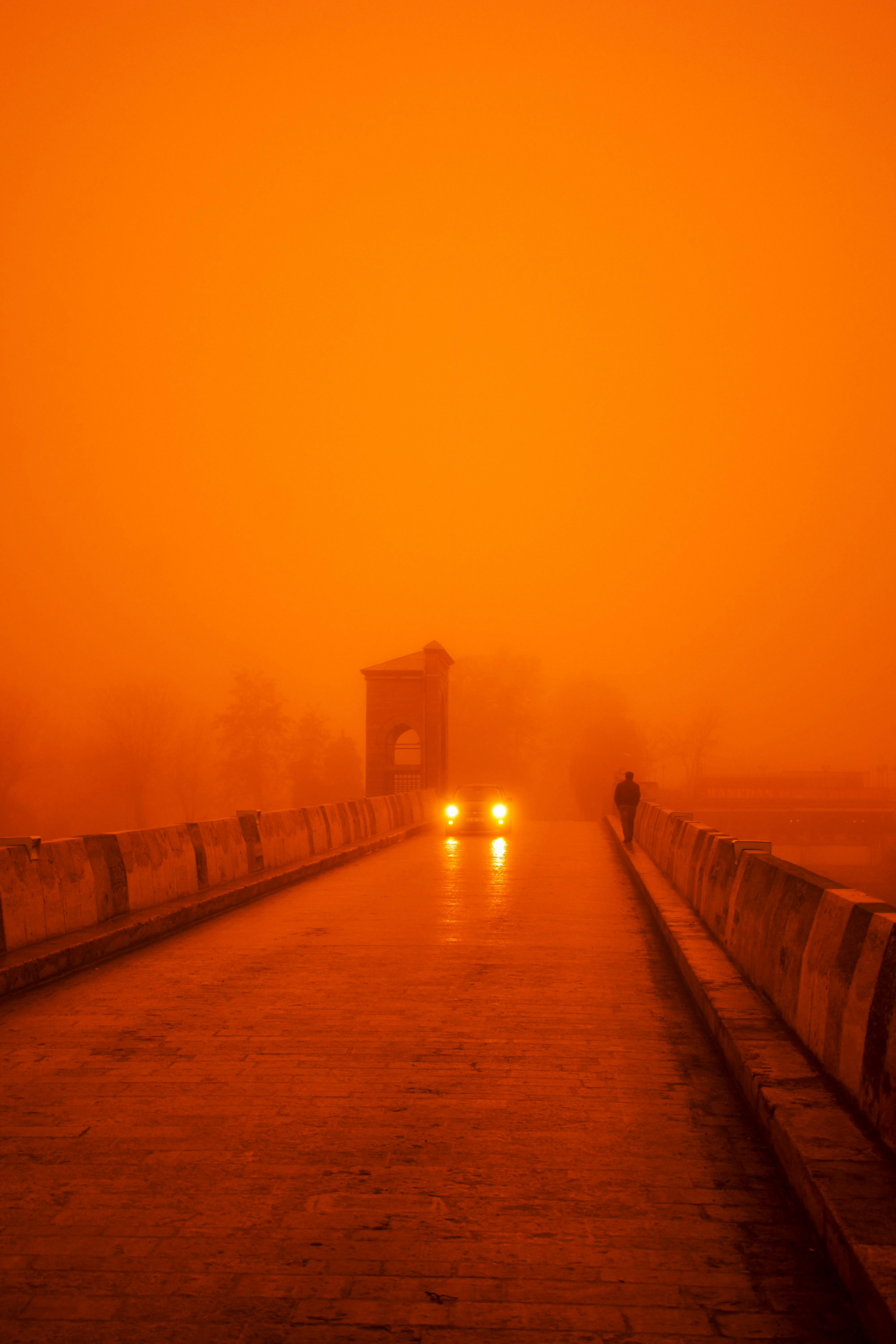 Ember Veil Bridge: Headlights through a Tangerine Fog