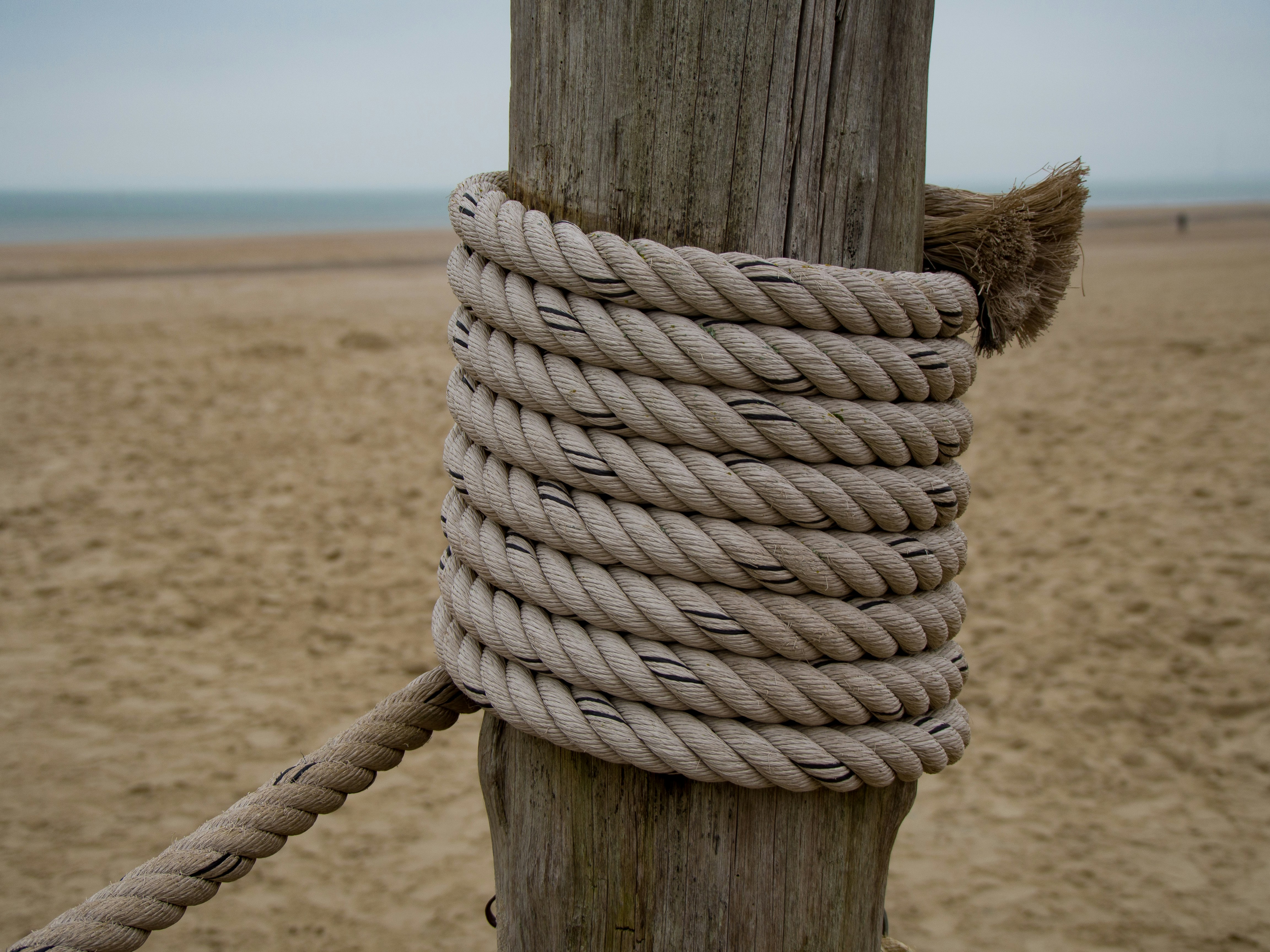 A rope wrapped around a wooden post on a beach photo – Free Rope Image ...