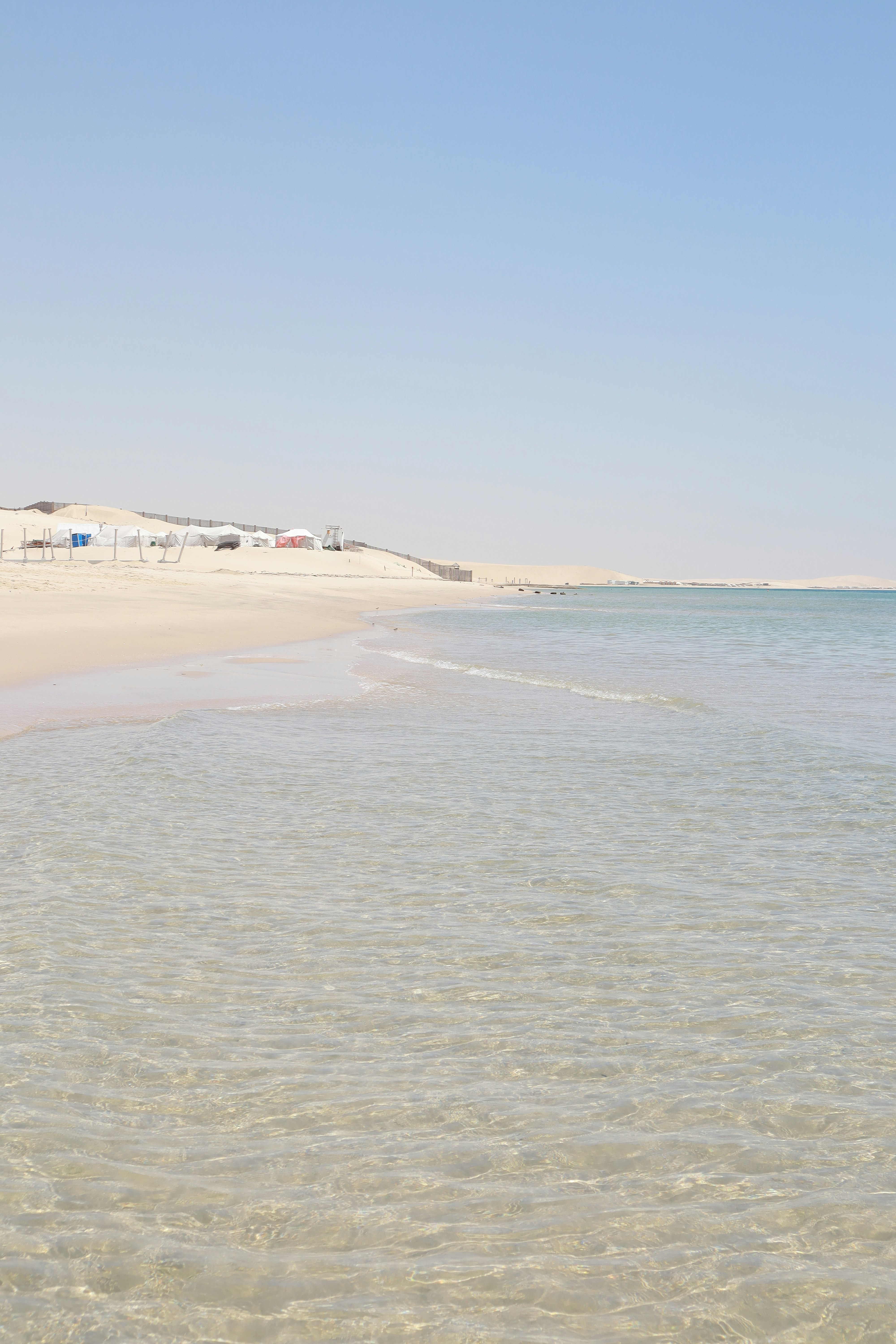 Whispering Shoreline: Glassy Sea and Dune Row Under a Pale Sky