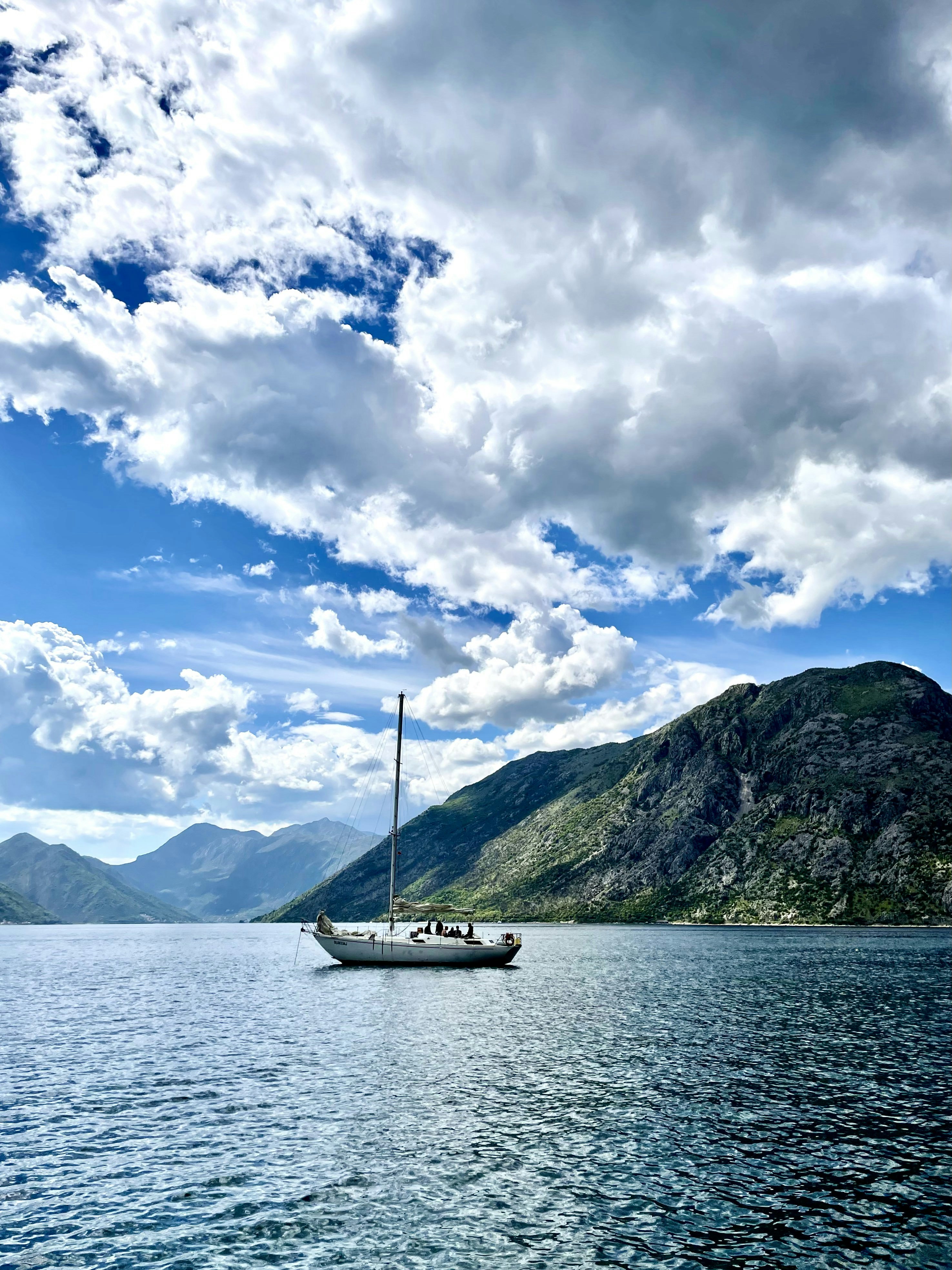 Lone Sailboat in a Fjord Beneath a Sky of Moving Clouds