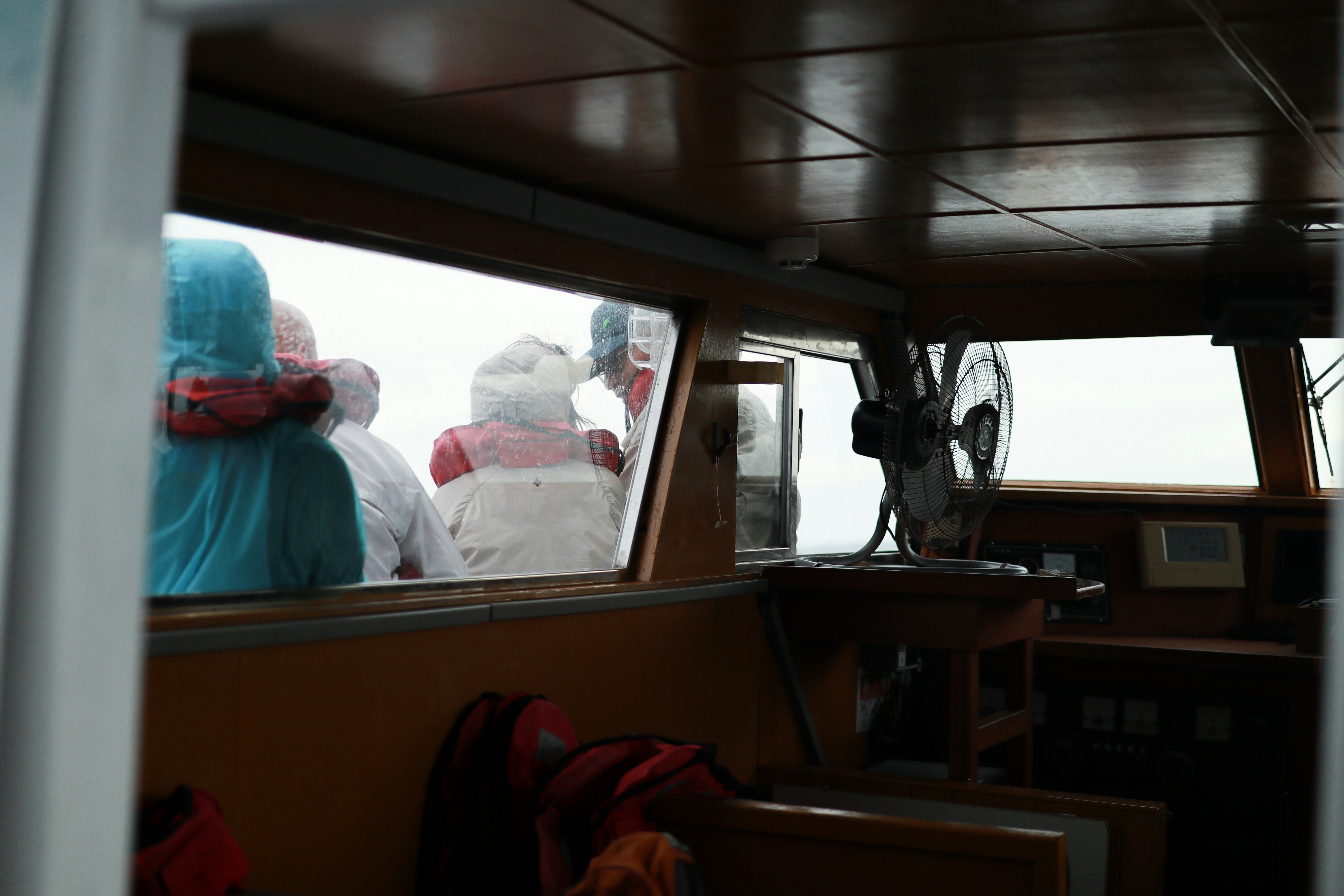 Window Watchers: Passengers Peering Through a Rainy Boat Cabin Window