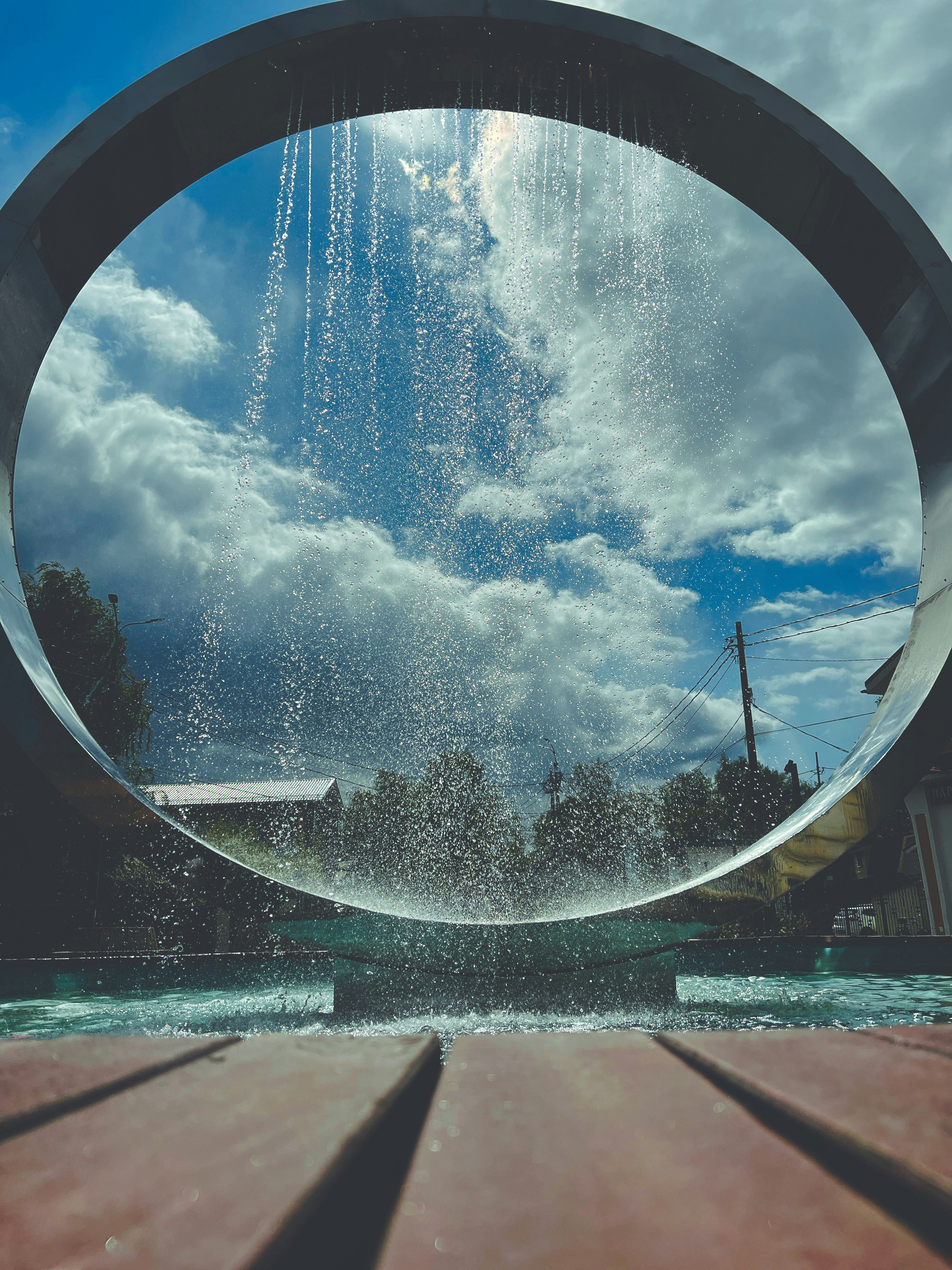 Ringed Cascade: droplets suspended inside a sunlit circular sculpture