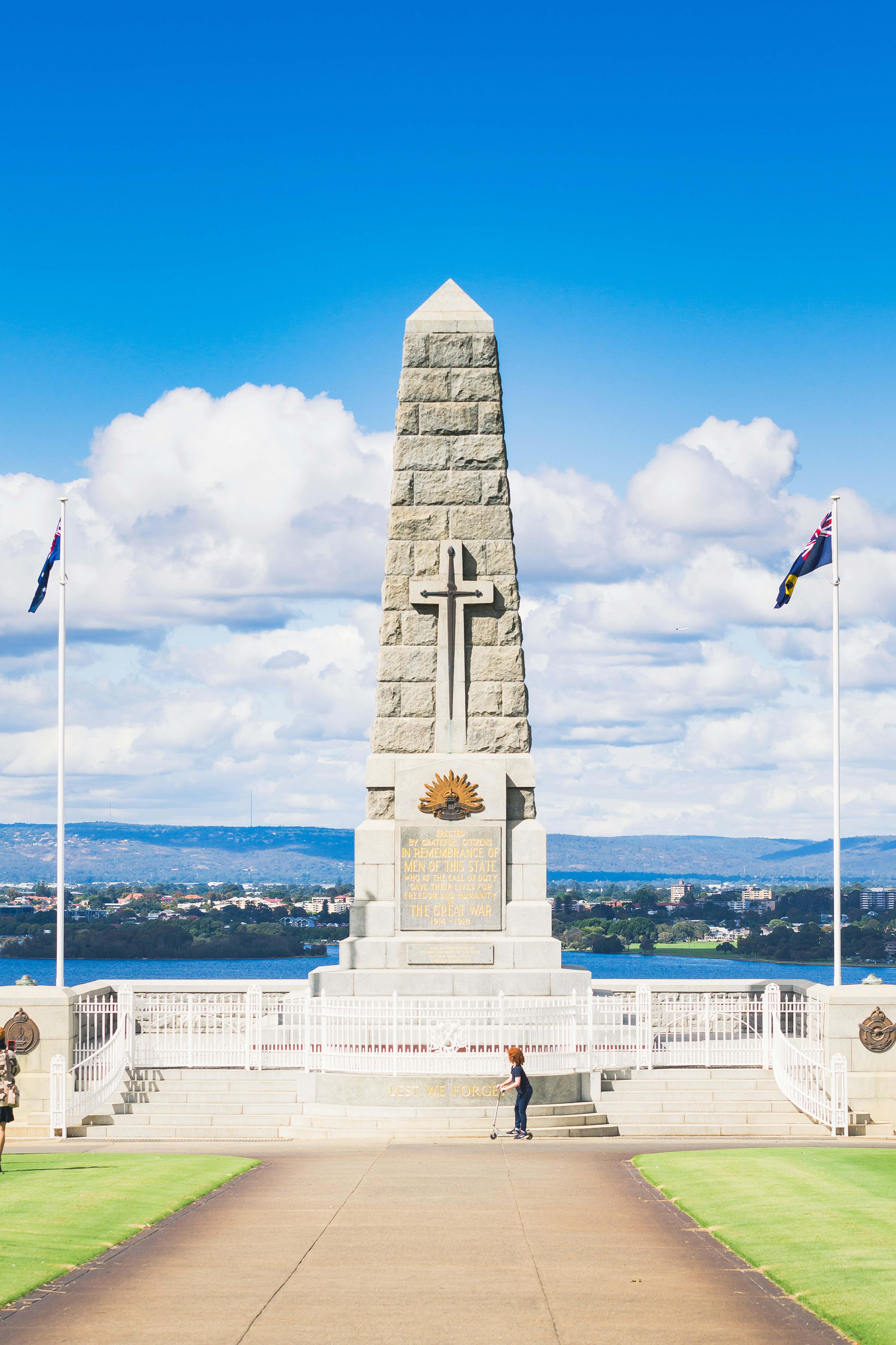 Coastal Obelisk Memorial Framed by Flags Under a Clear Blue Sky