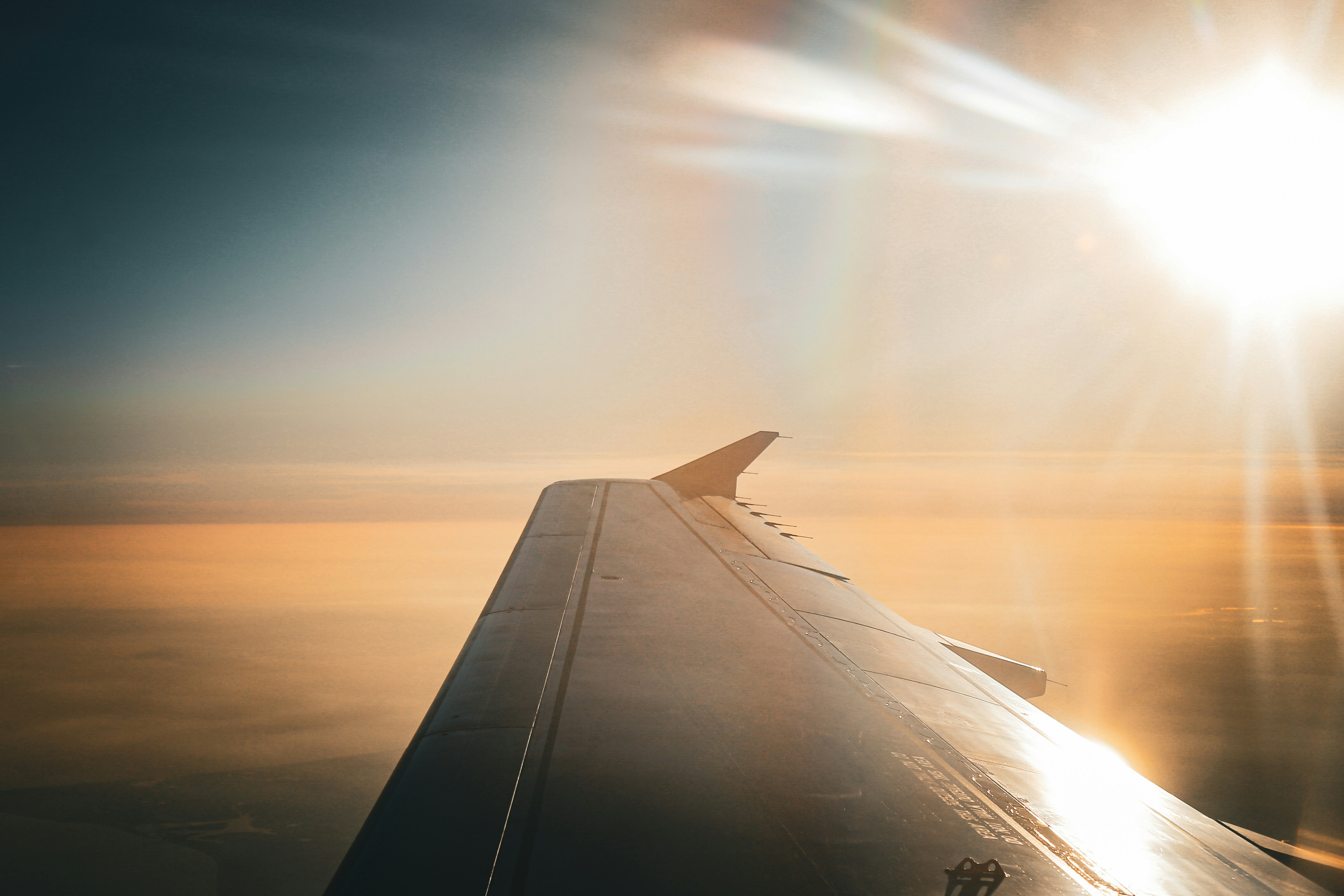 The wing of an airplane as the sun shines through the clouds photo ...