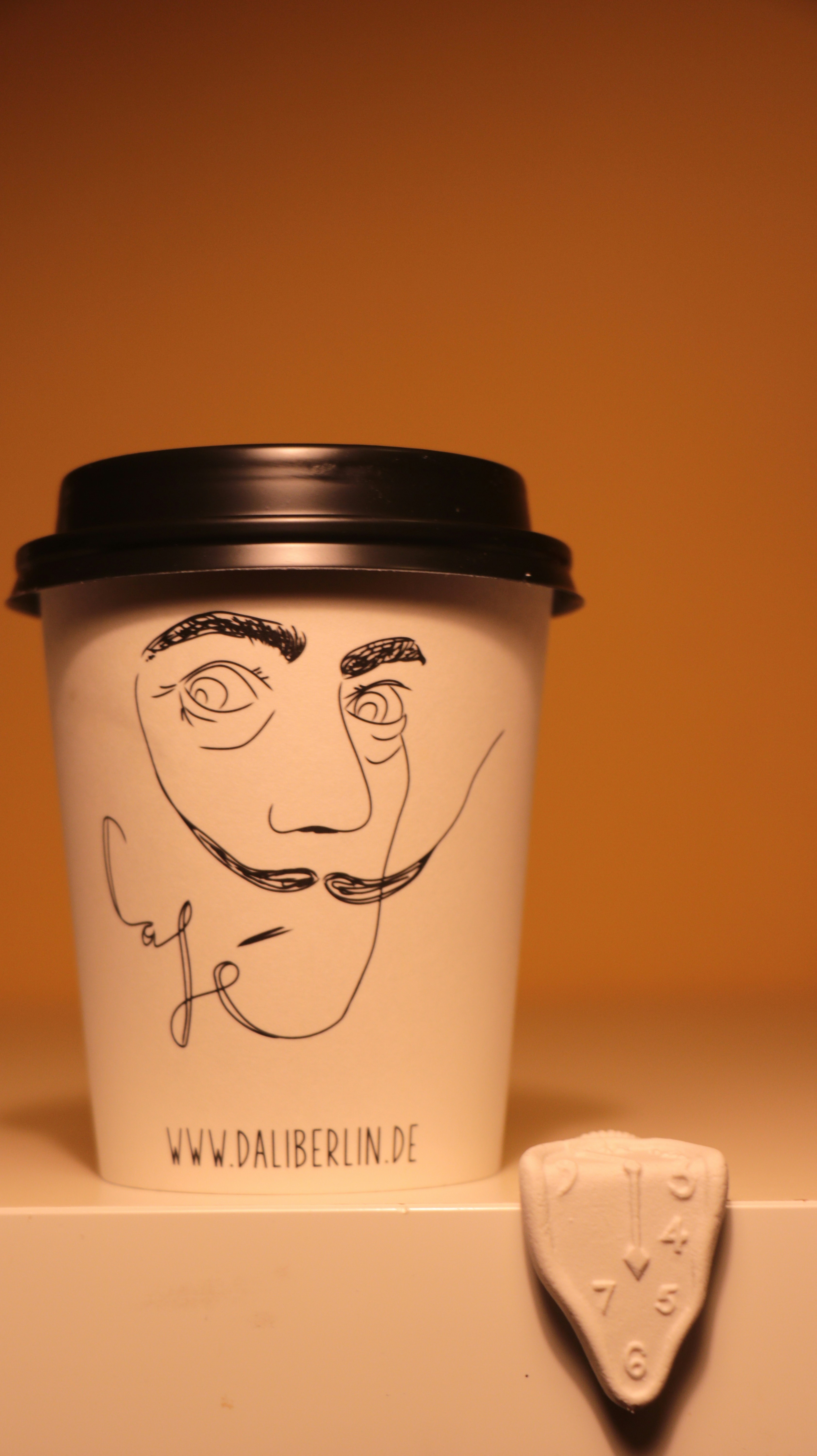 Amber-glow close-up: a to-go cup with a line-drawn face