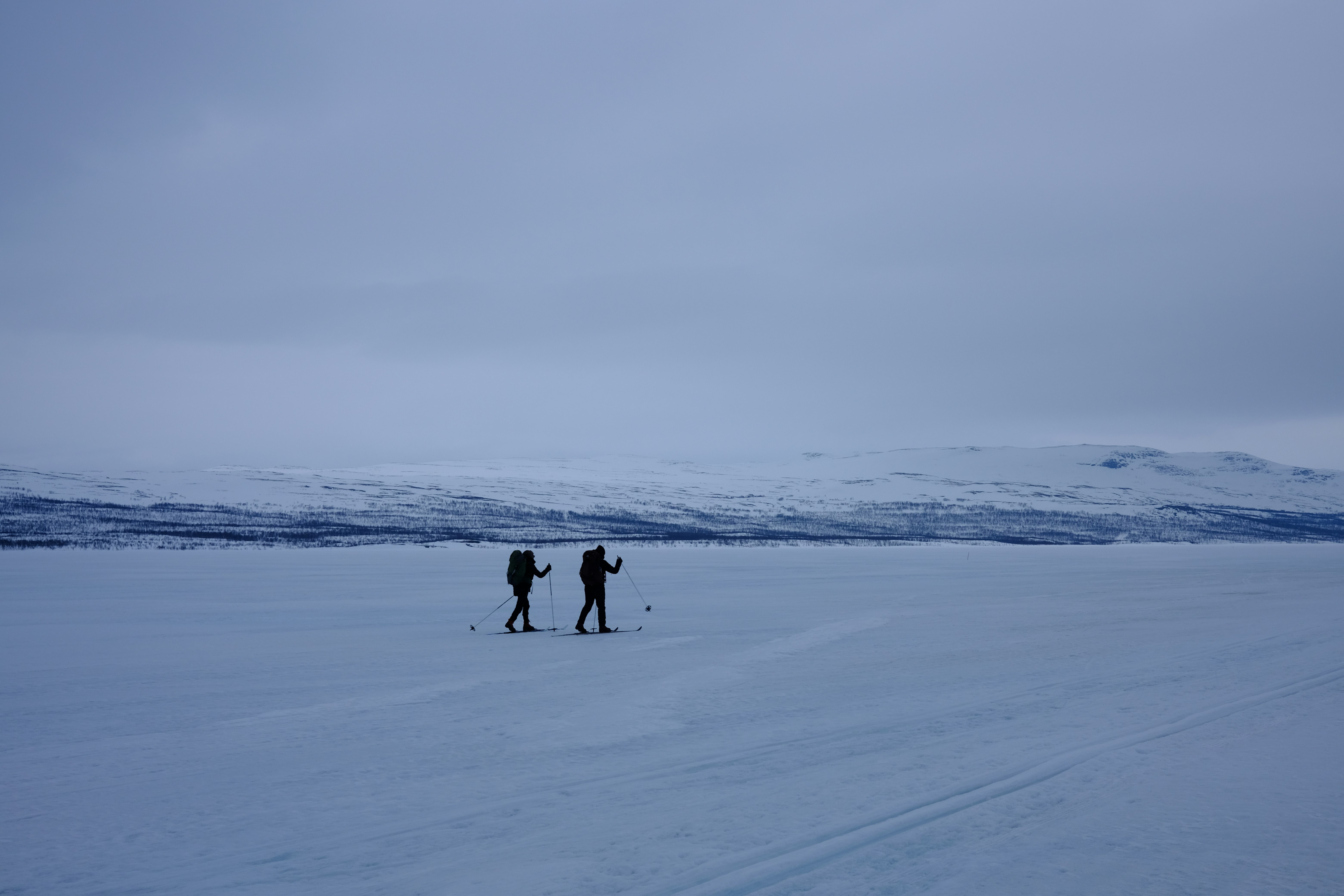 A couple of people walking across a snow covered field photo – Free ...