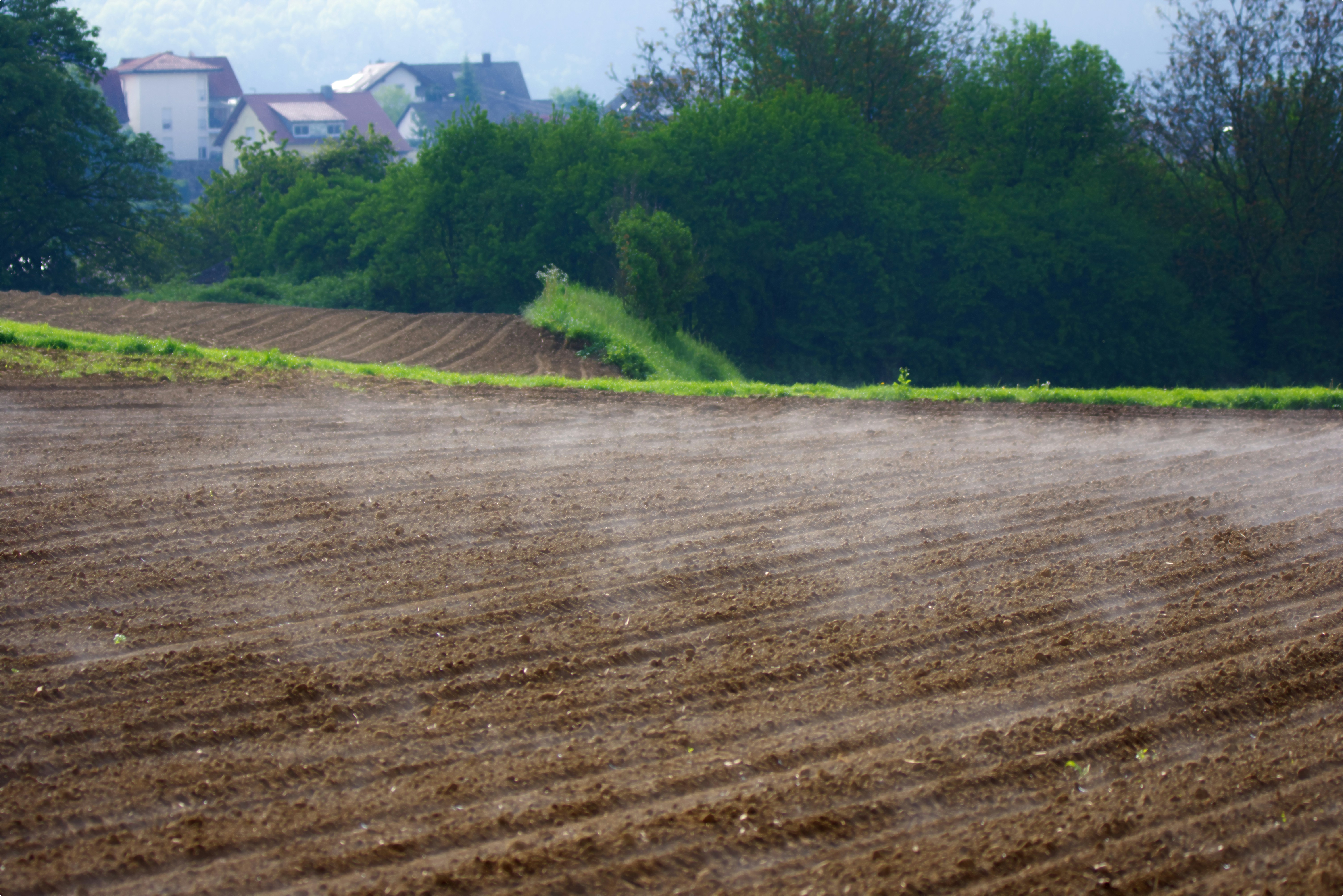 A plowed field with a house in the background photo – Free Soil Image ...