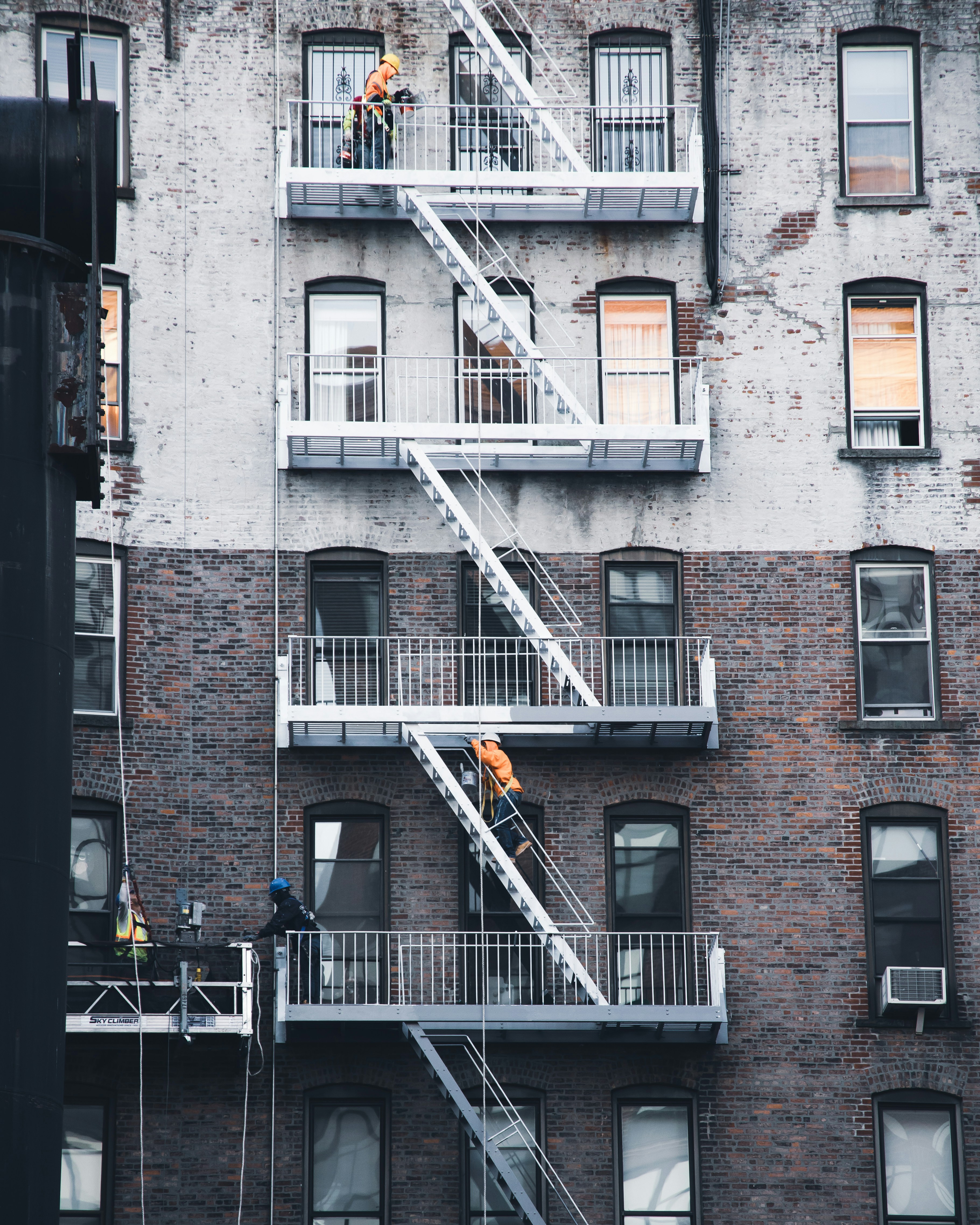 Fire escape choreography: workers scale the brick shell
