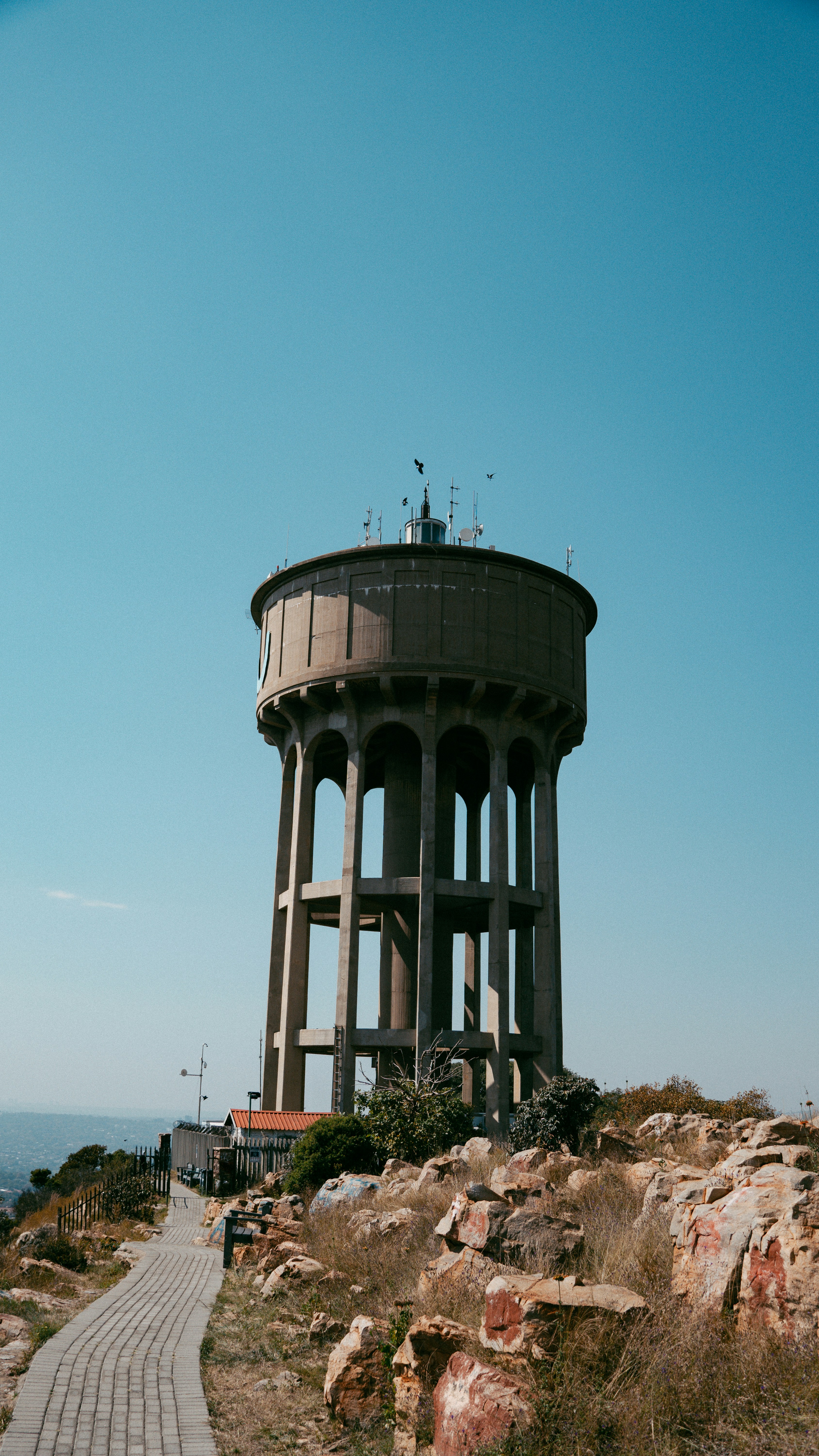 Coastal Sentinel: A Concrete Water Tower Rising Above Rugged Rocks and a Quiet Path