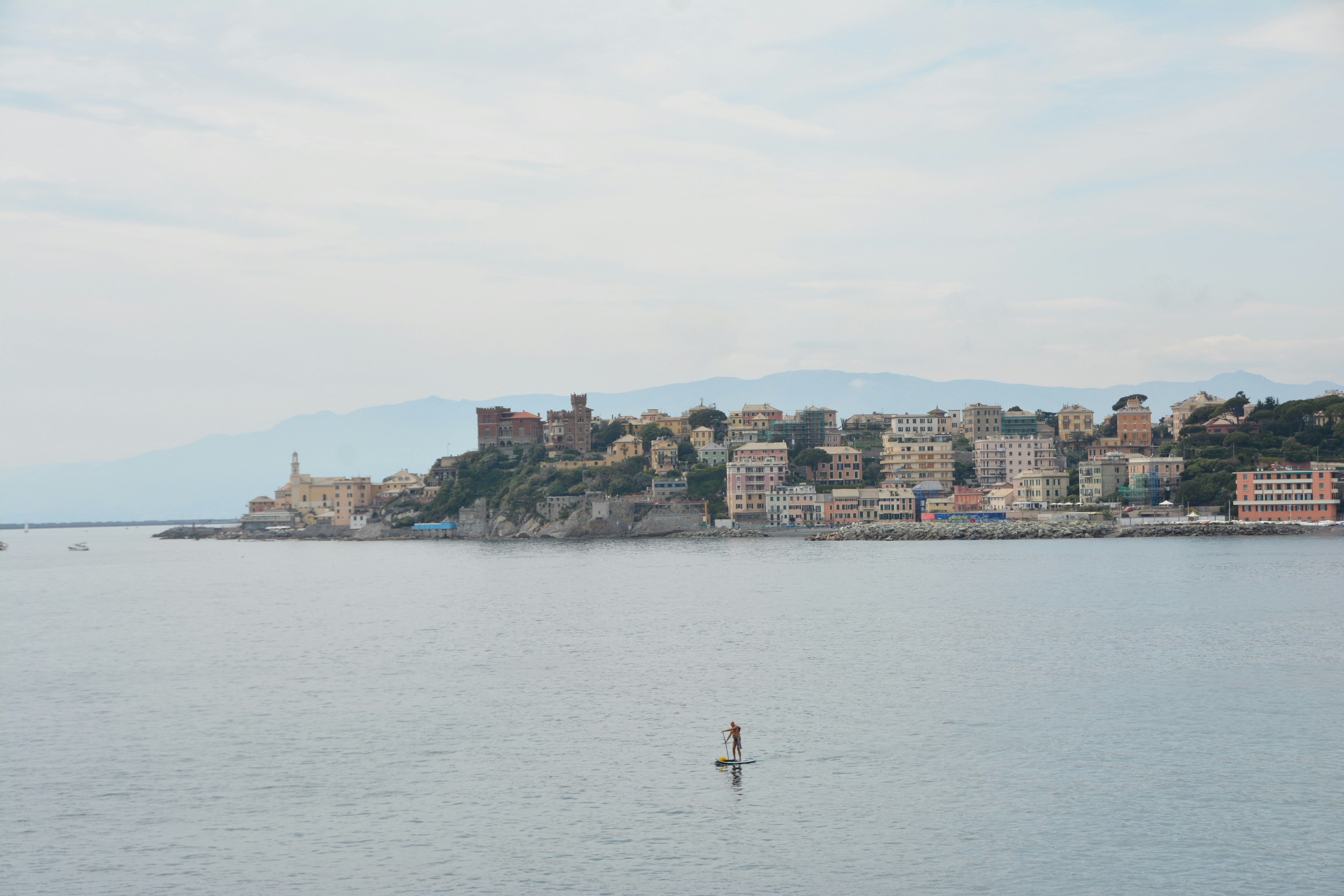 Harbor Silhouette: A lone paddler beneath a cliffside town