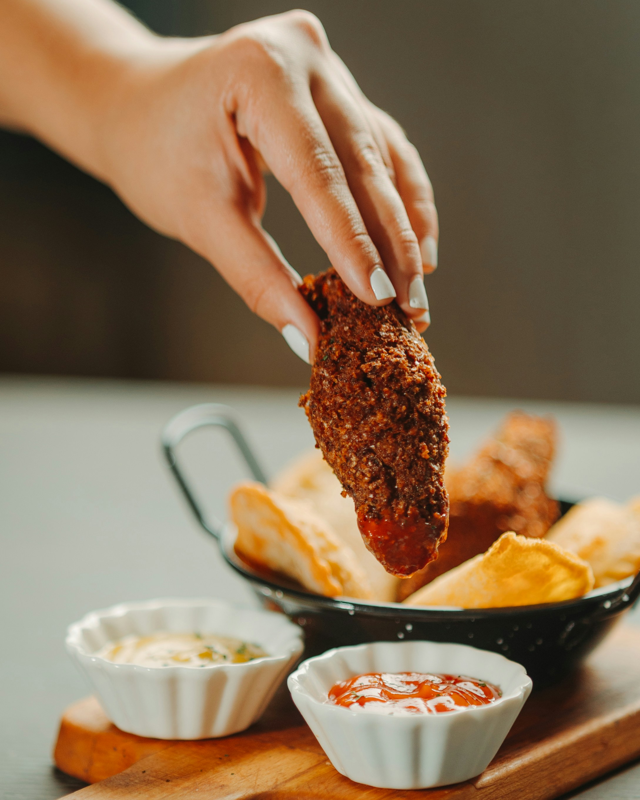 The Crispy Grab: A Golden Chicken Bite Hovering Over a Duo of Dips