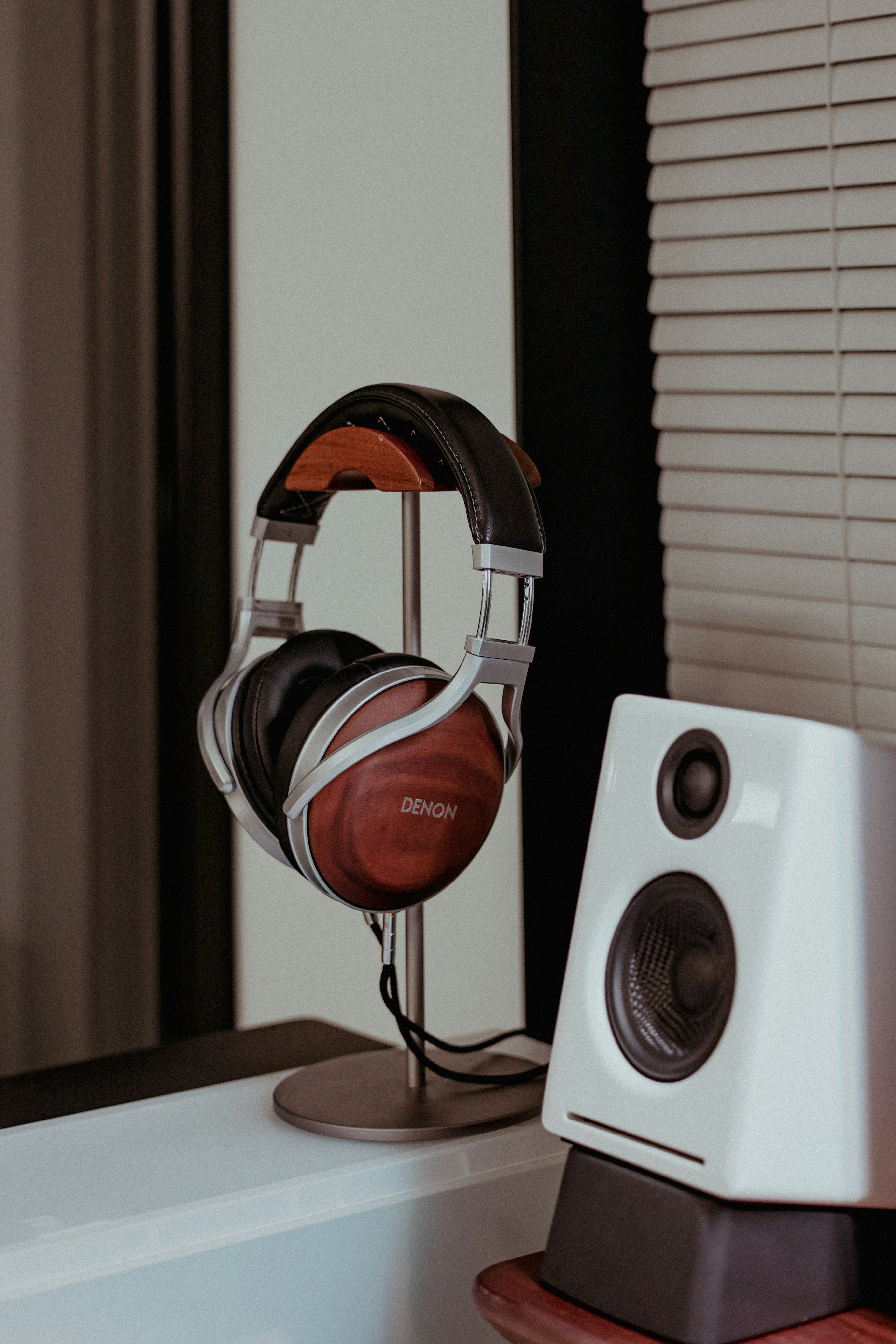 Denon Headphones on a Metal Stand: A Minimalist Desk Portrait in Warm Indoor Light