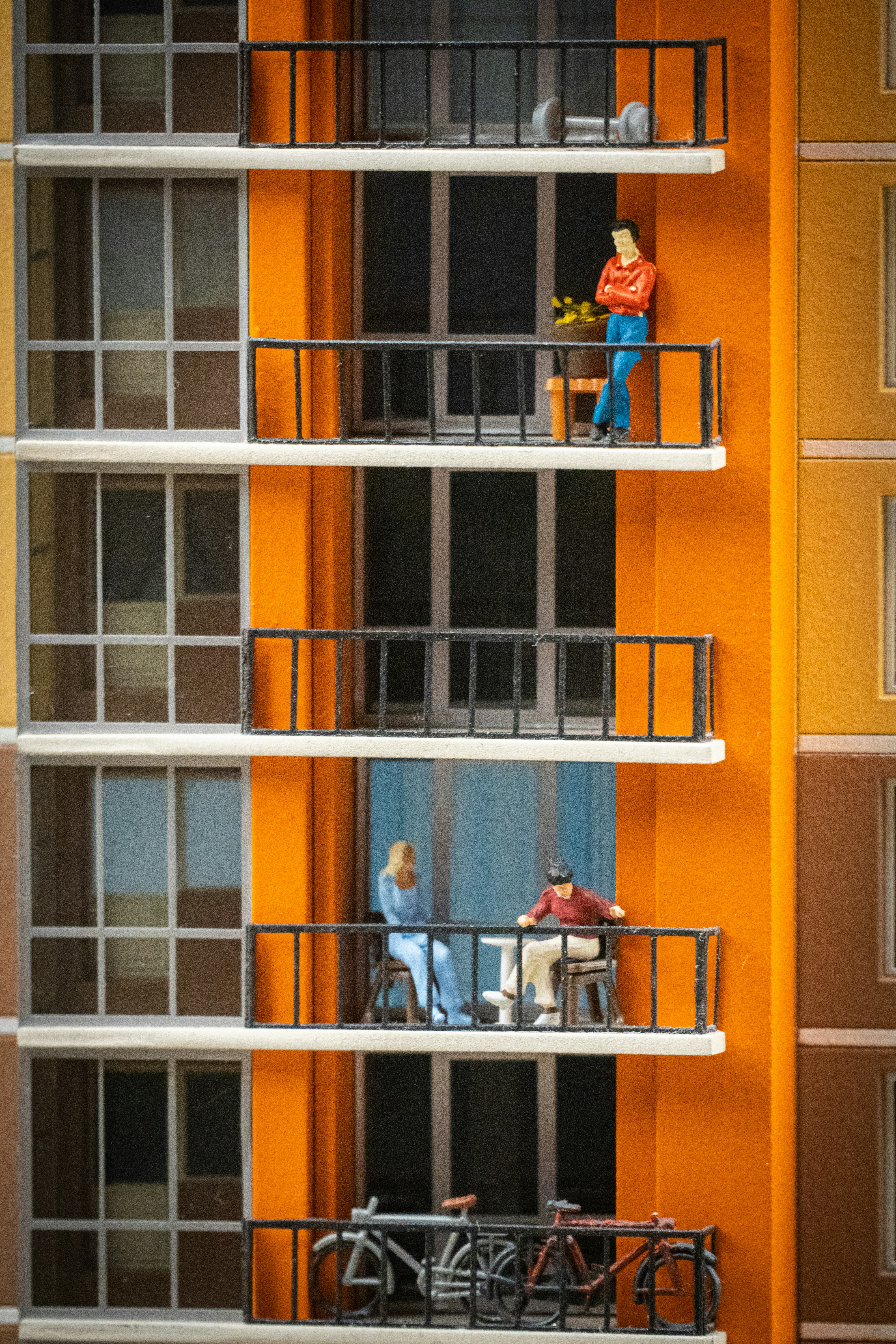 Color Blocked Balcony: Figures Drawn Across a Bright Orange Facade