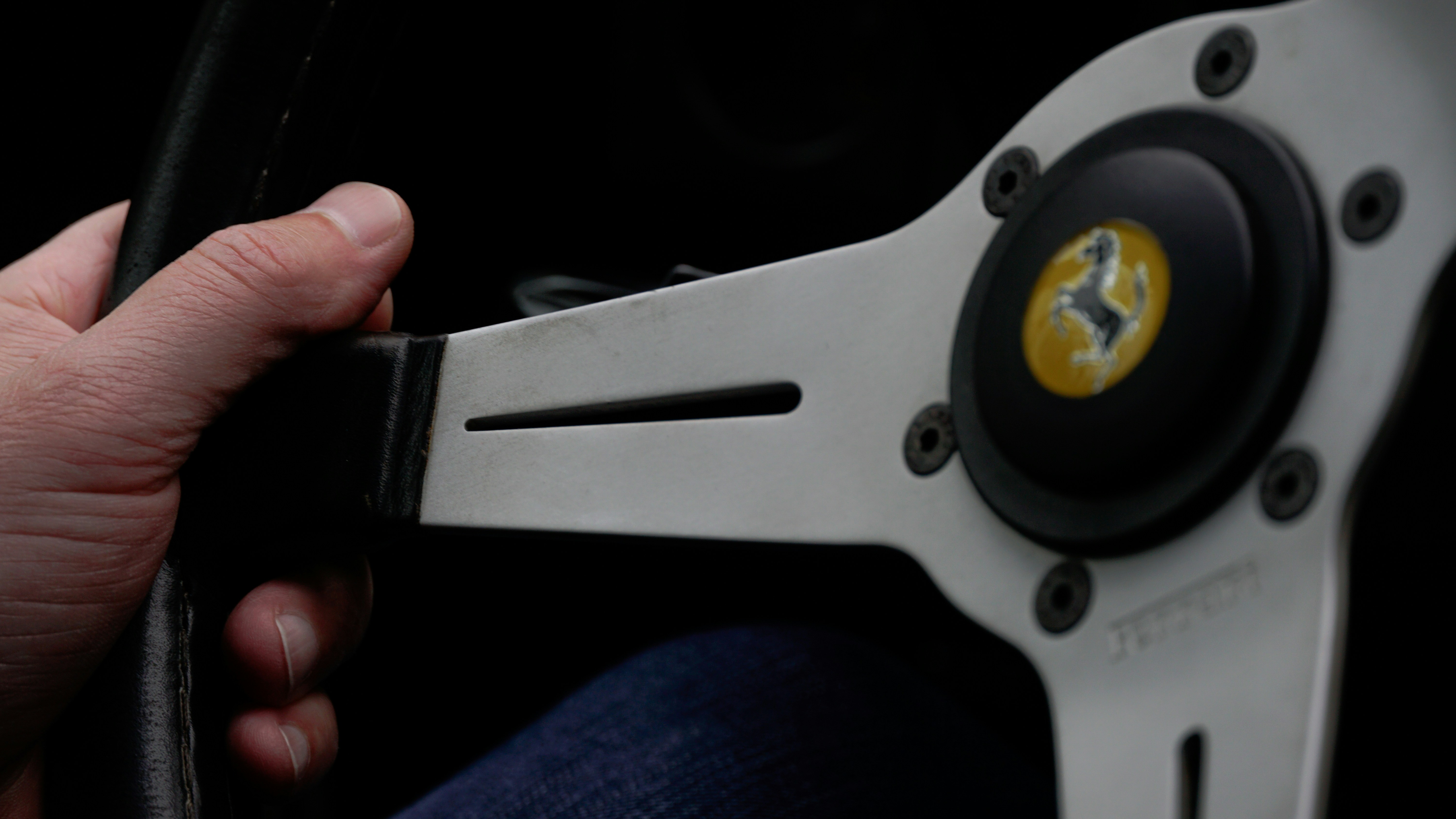 Gripped Ferrari Wheel: A Close-Up of Hand, Metal, and Crest