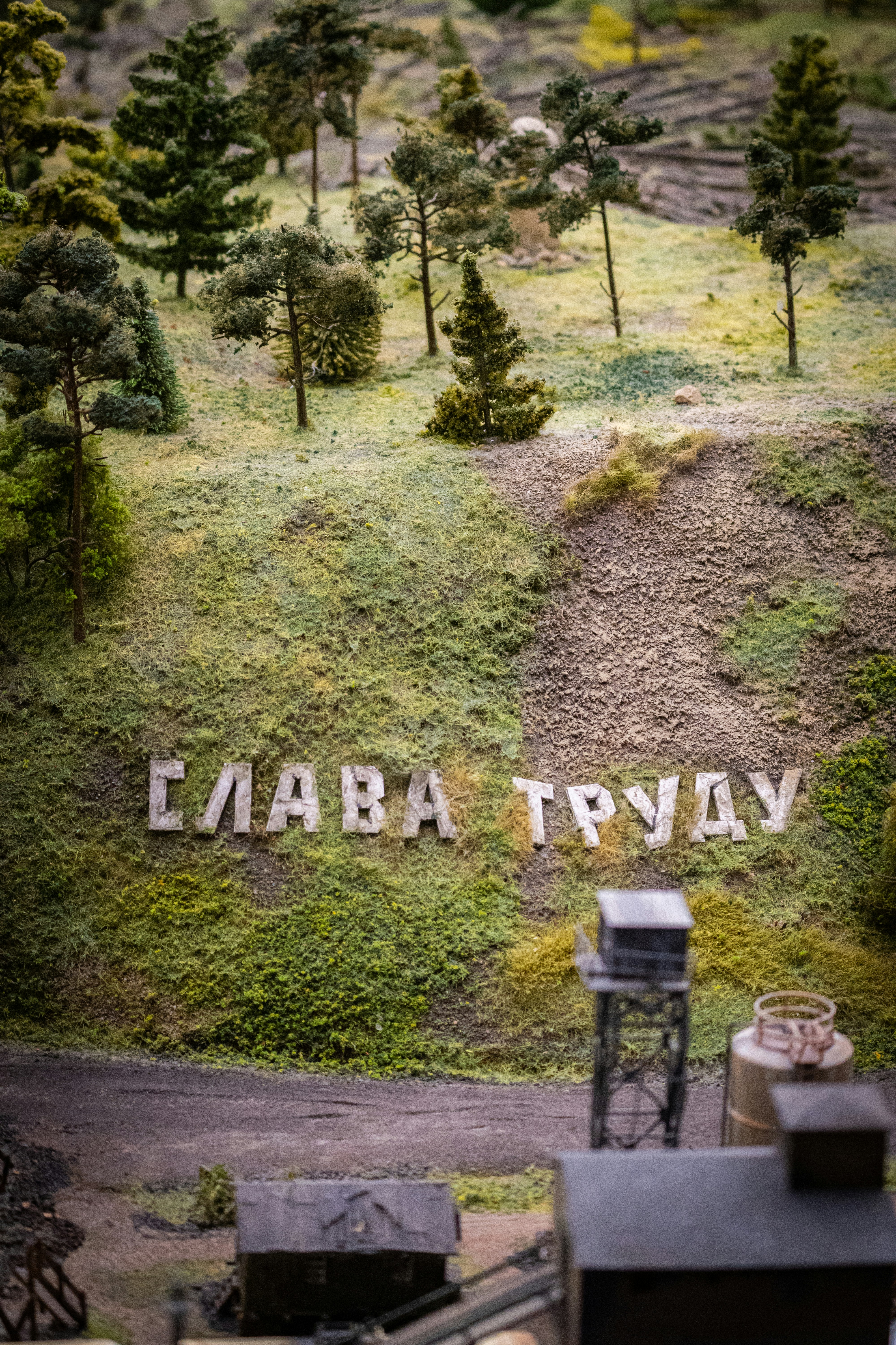 Green hillside with Cyrillic signage and rustic industrial foreground