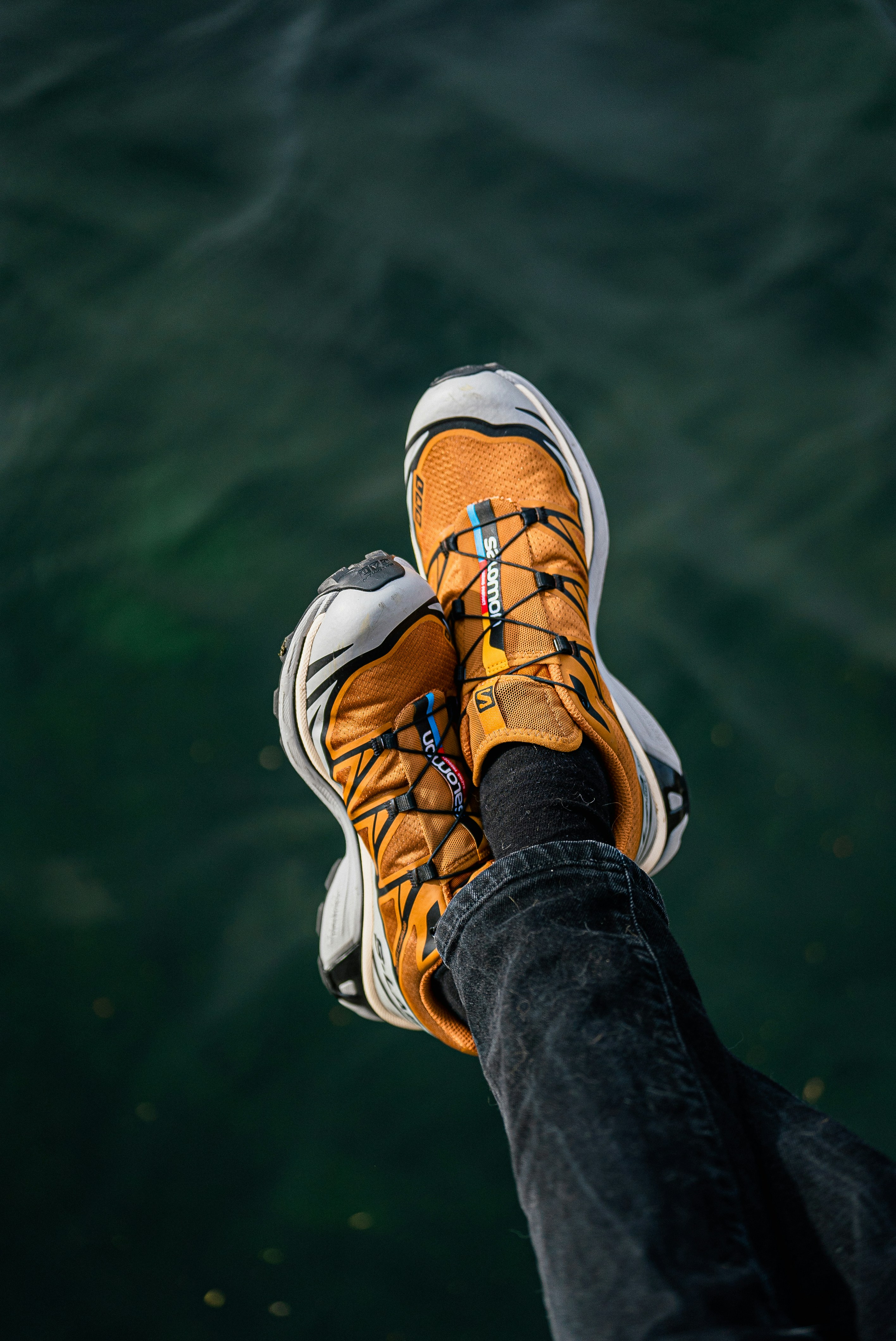 Suspended Steps: Orange Trail Shoes Hover Over Emerald Water