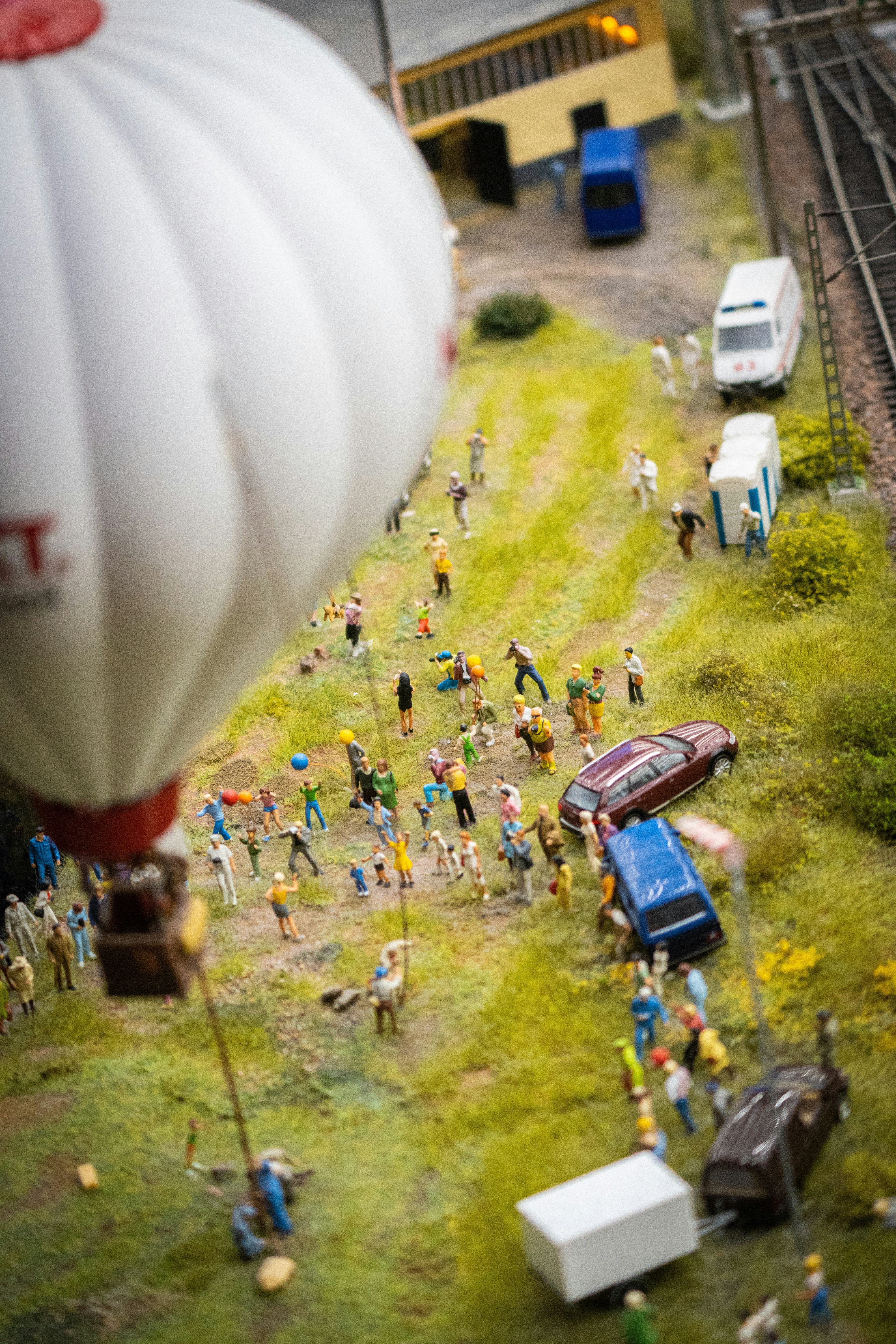 Miniature Crowd Beneath a Lifting Balloon