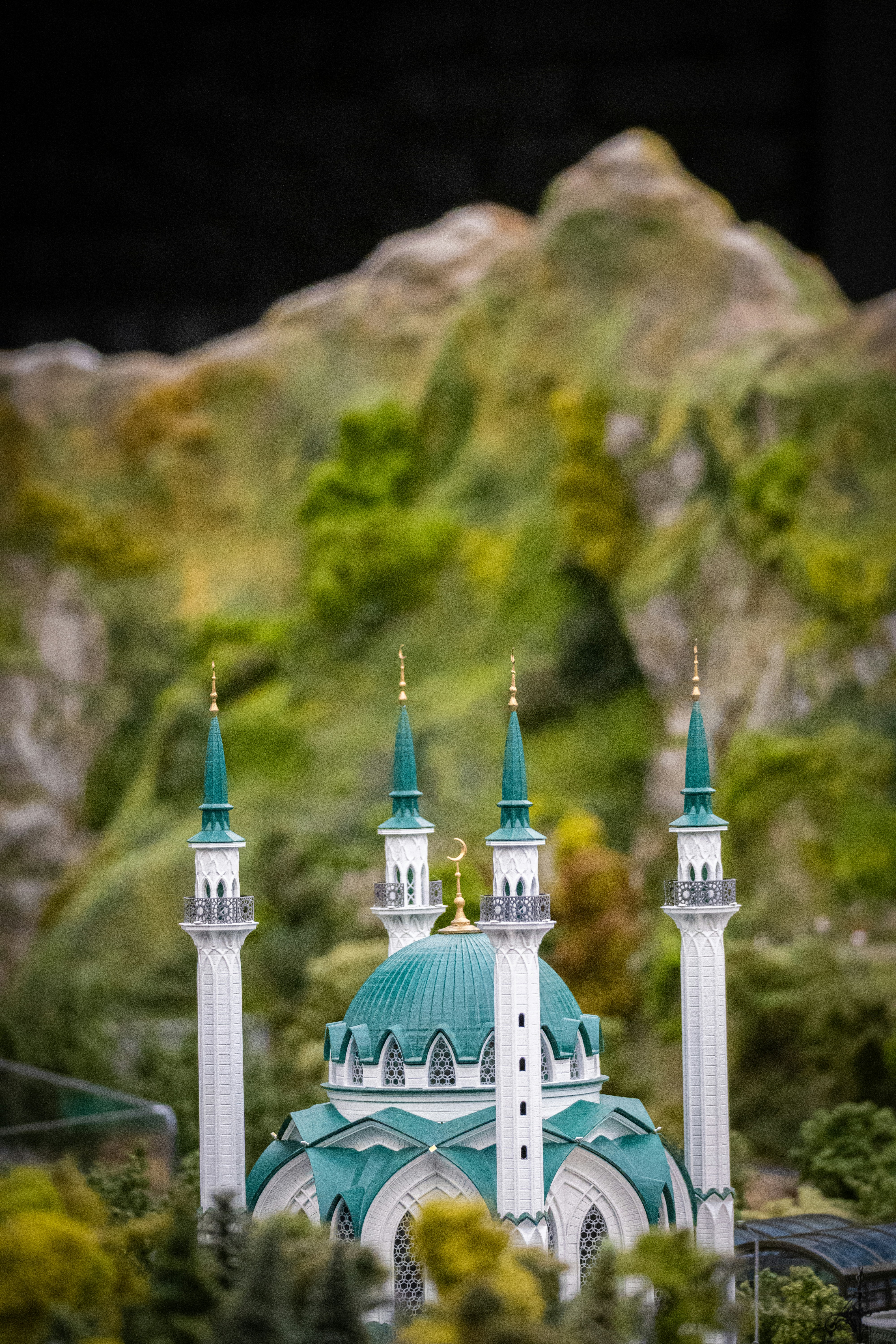 Turquoise Domes Rising Among Green Cliffs: A Miniature Mosque in Focus