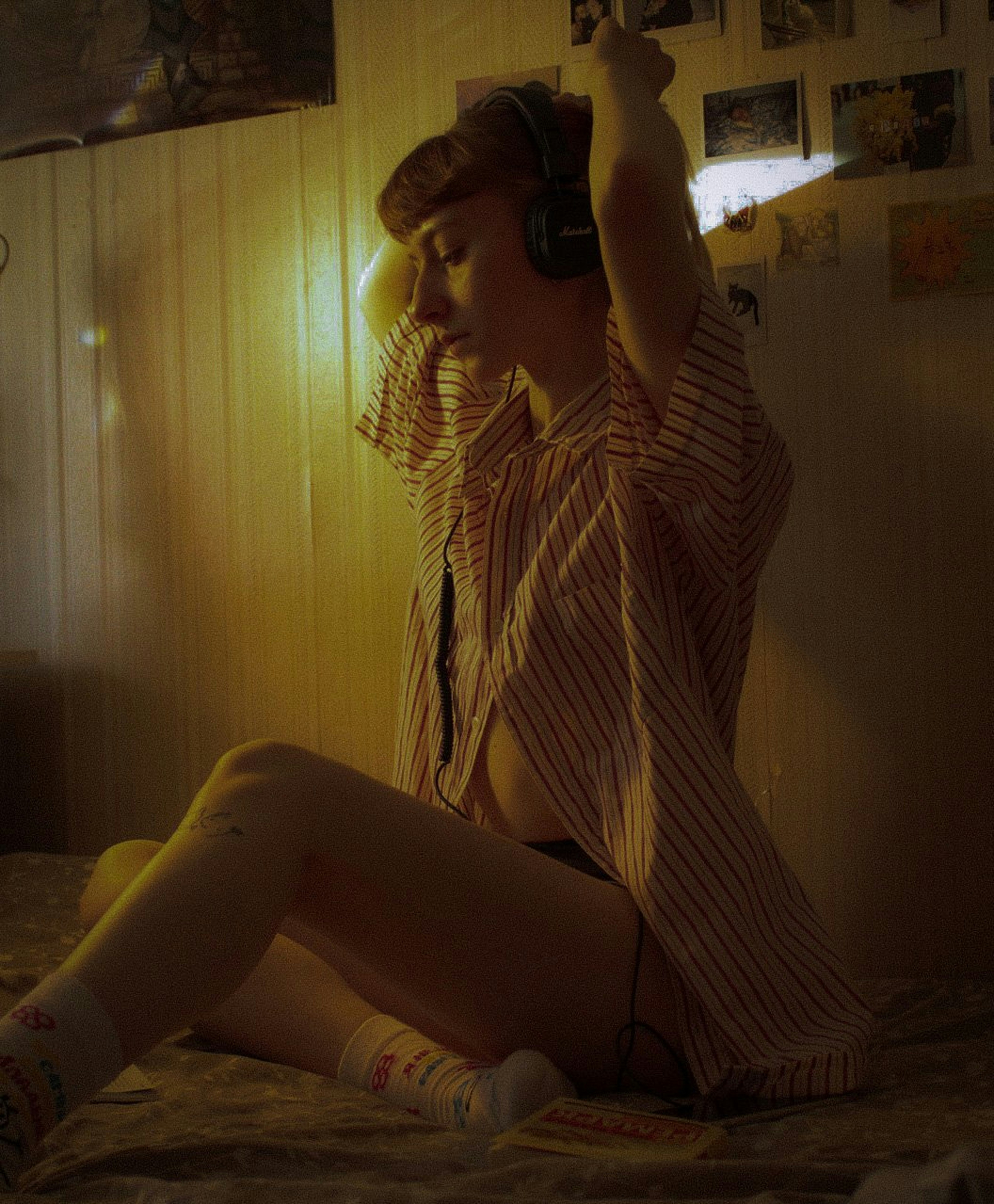 Amber-lit Contemplation: a dim-bedroom portrait with headphones