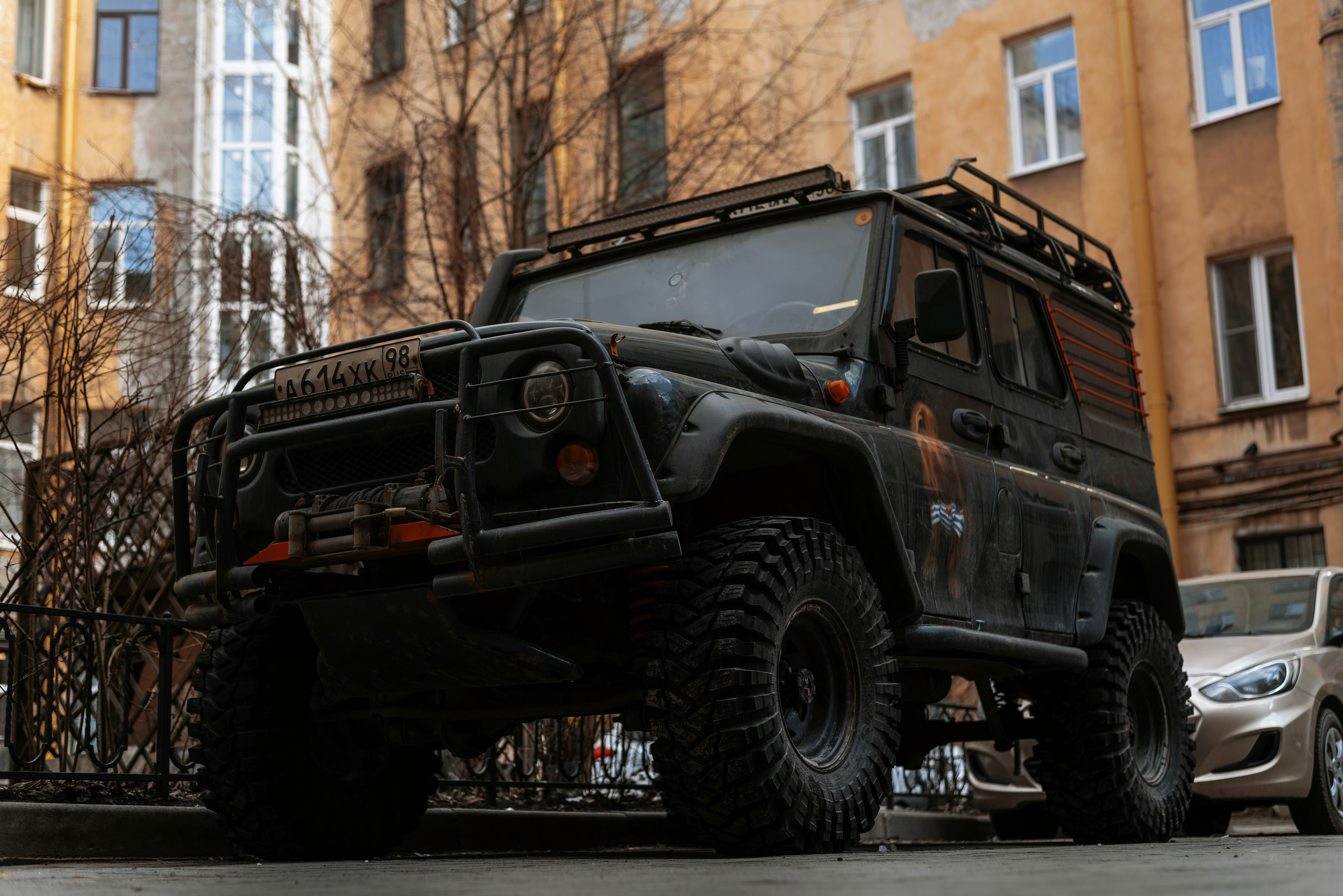 City Gatekeeper: A Mud-Splashed Off-Road Rig Beside the Brick Facade